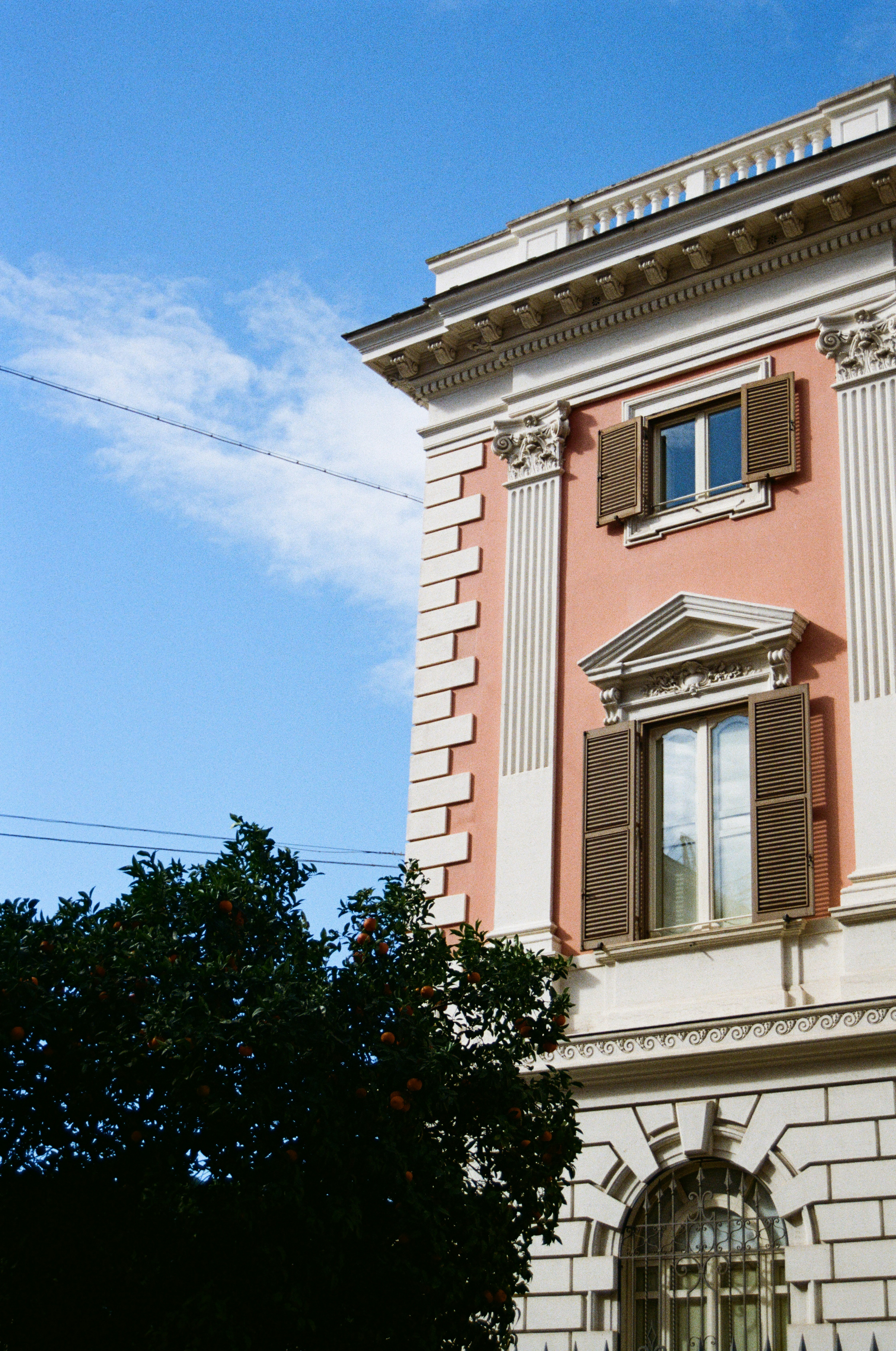 Facade in Focus: Classical Corner with Pink Stucco and Shuttered Windows