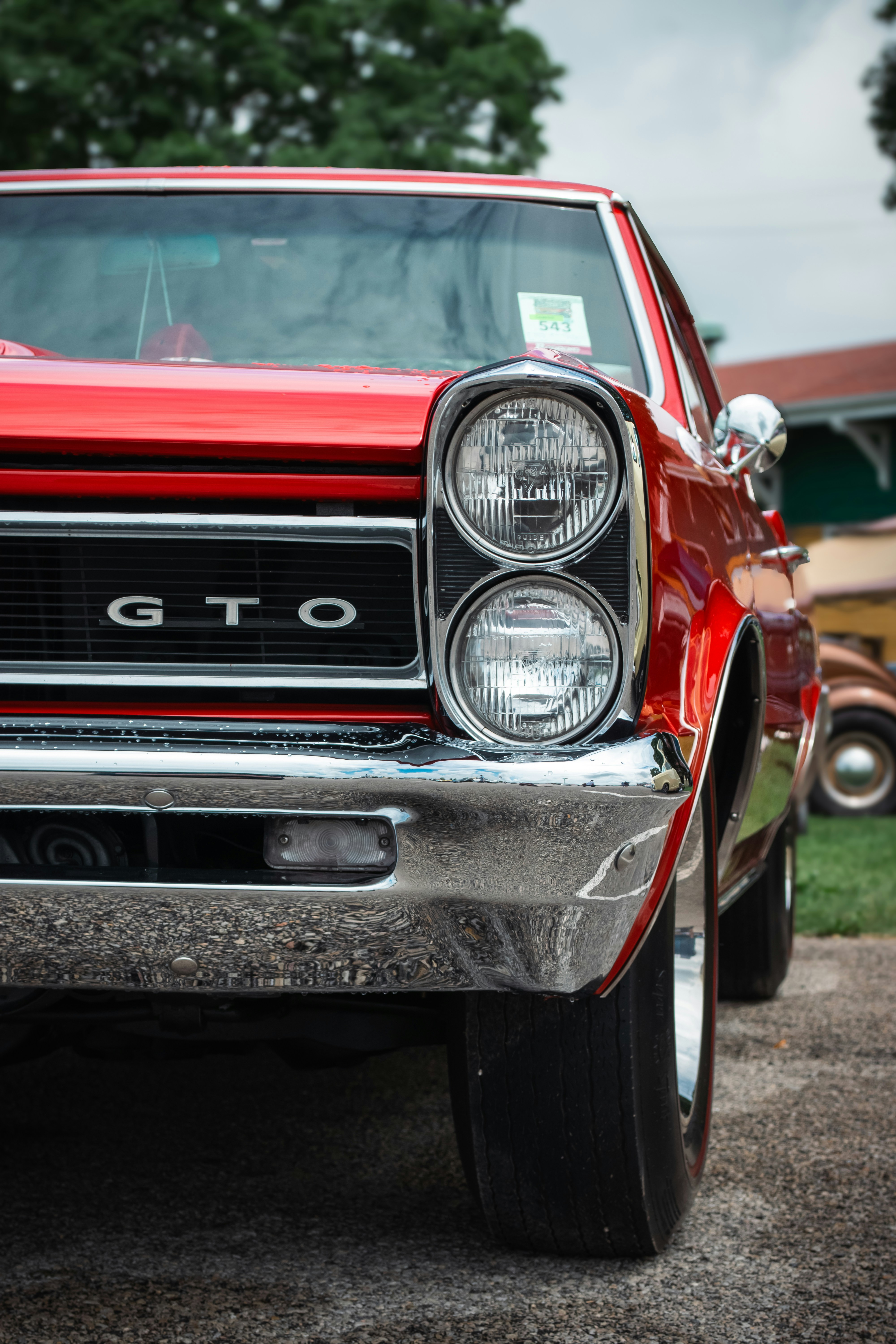Close-Up of a Chrome Red Pontiac: Classic Car Front Halved in a Show Scene