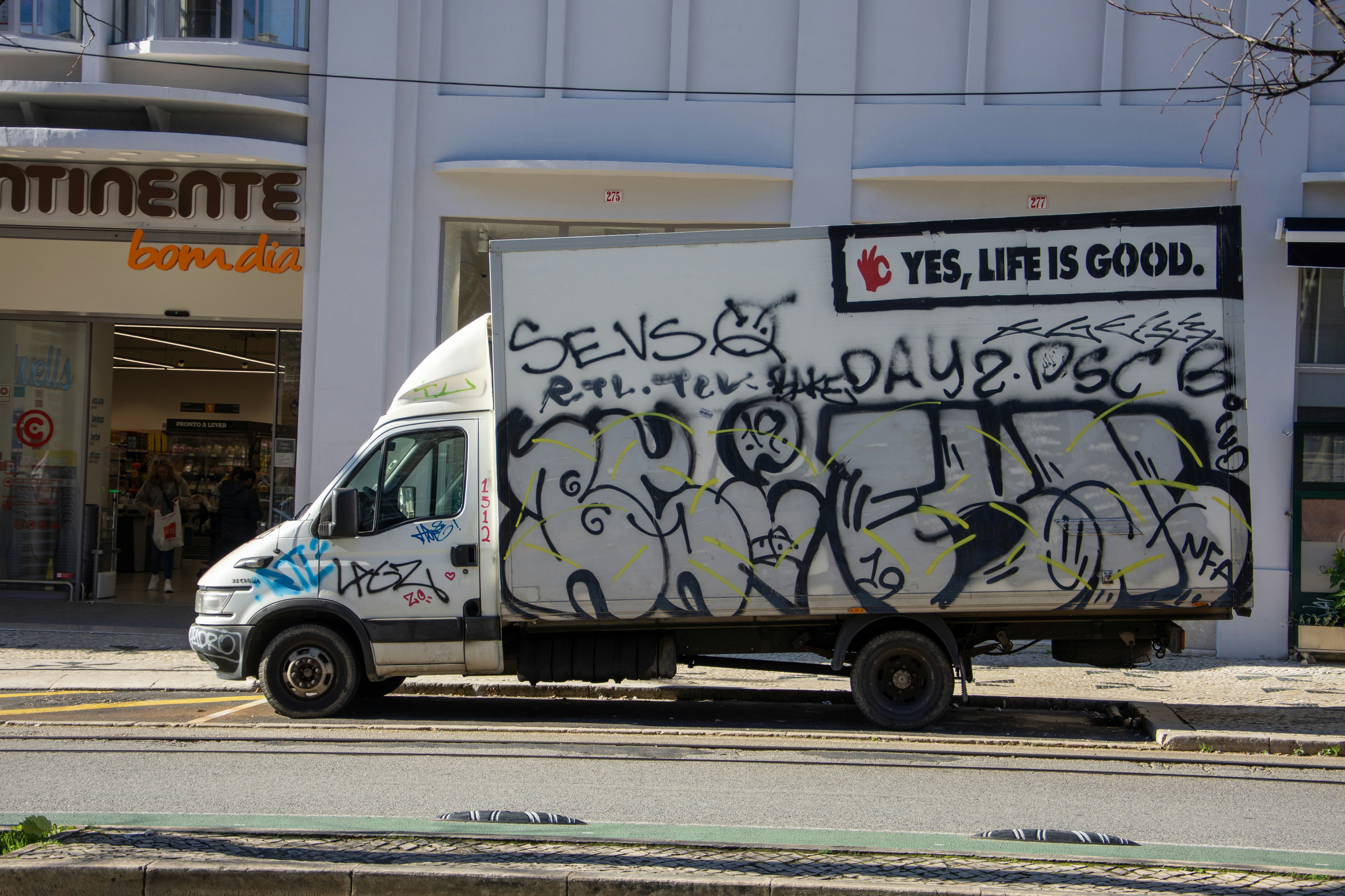 Graffiti-etched delivery: a mural-lit truck rests before a storefront