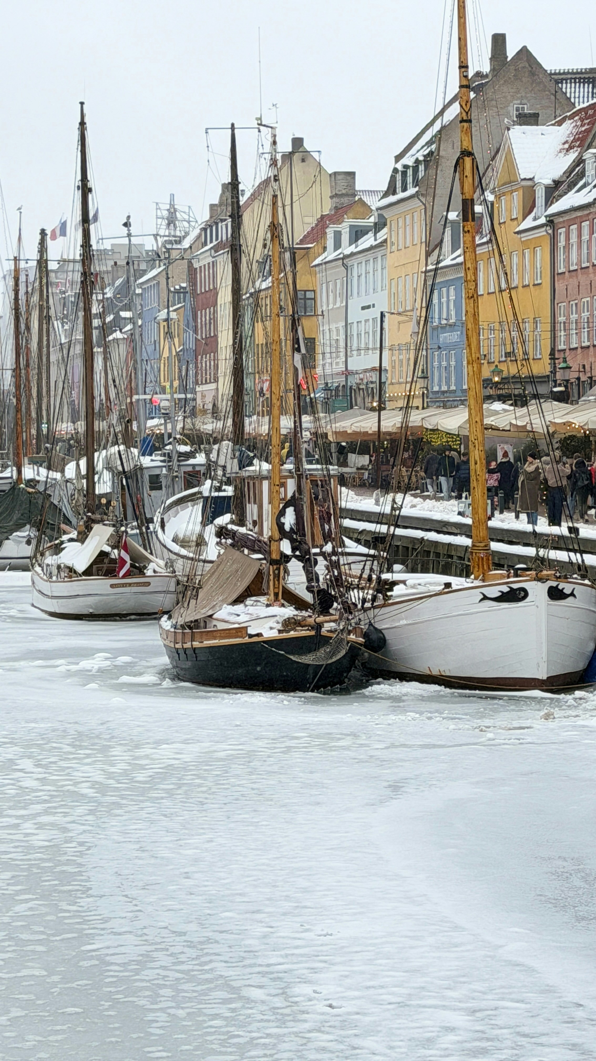 Colorful waterfront with classic sailing ships along a snow-dusted quay