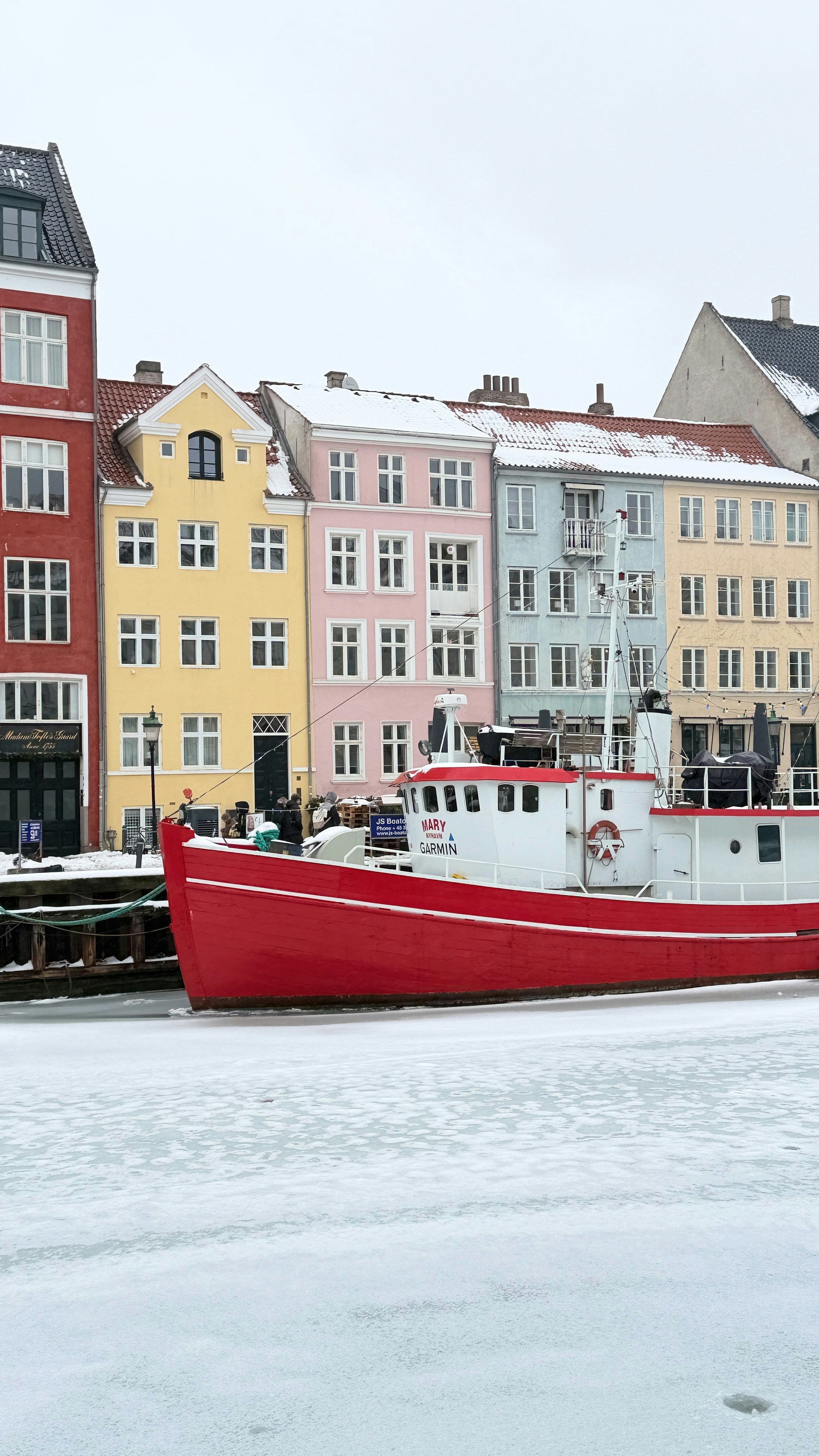 Vibrant Row Houses Framing a Snow-Dusted Docked Vessel