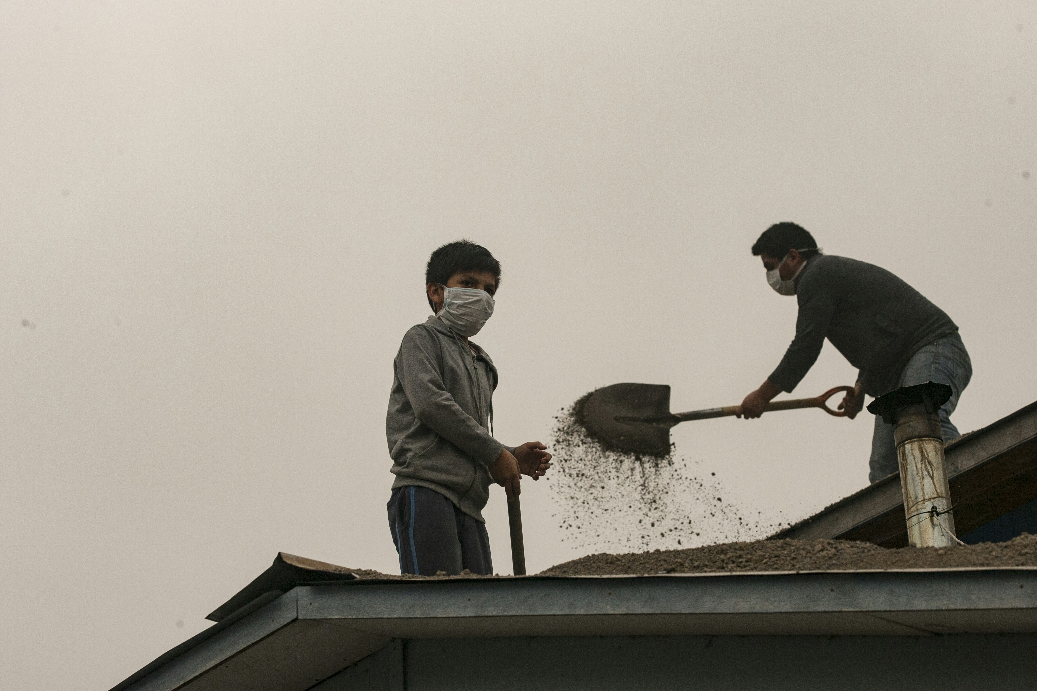 Dust and Duty: Workers Shovel Sand on a Rooftop