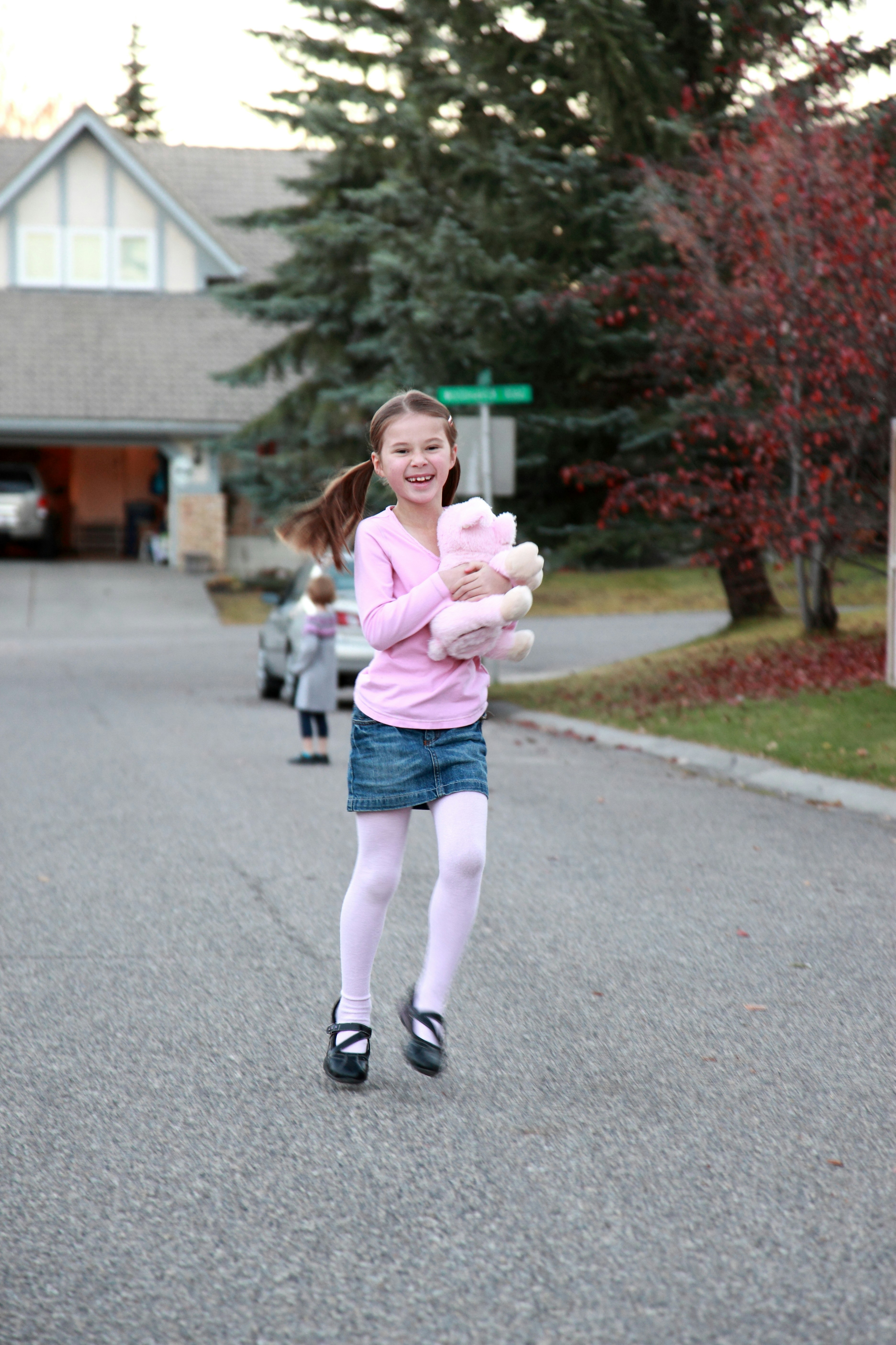 Joyful Run: A Girl in Pink with Plush Bear Dashes Toward Home