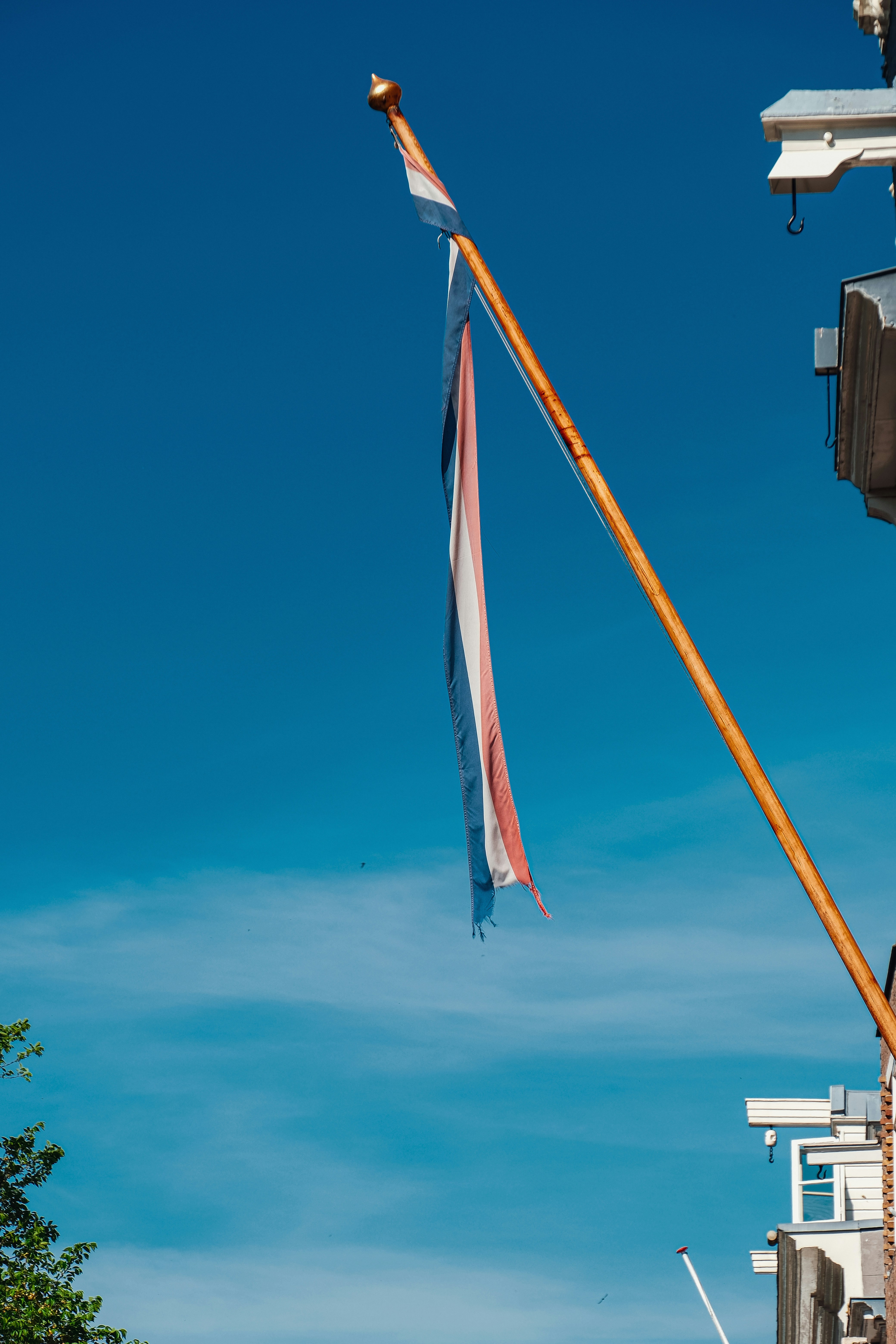 Pole with Tattered Flag Rippling Under a Clear Blue Sky