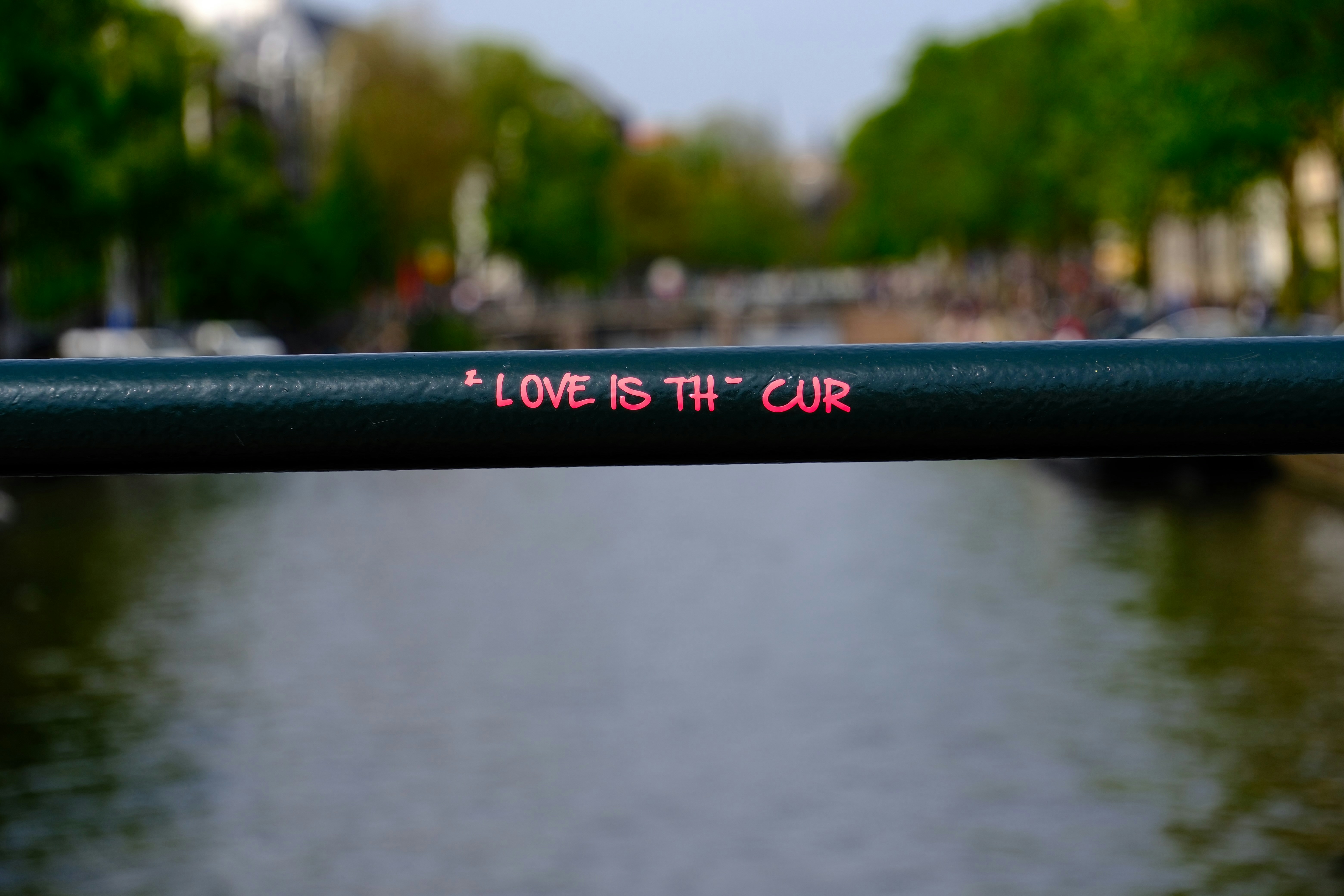 Graffiti on a Bridge Railing Over a Quiet Canal