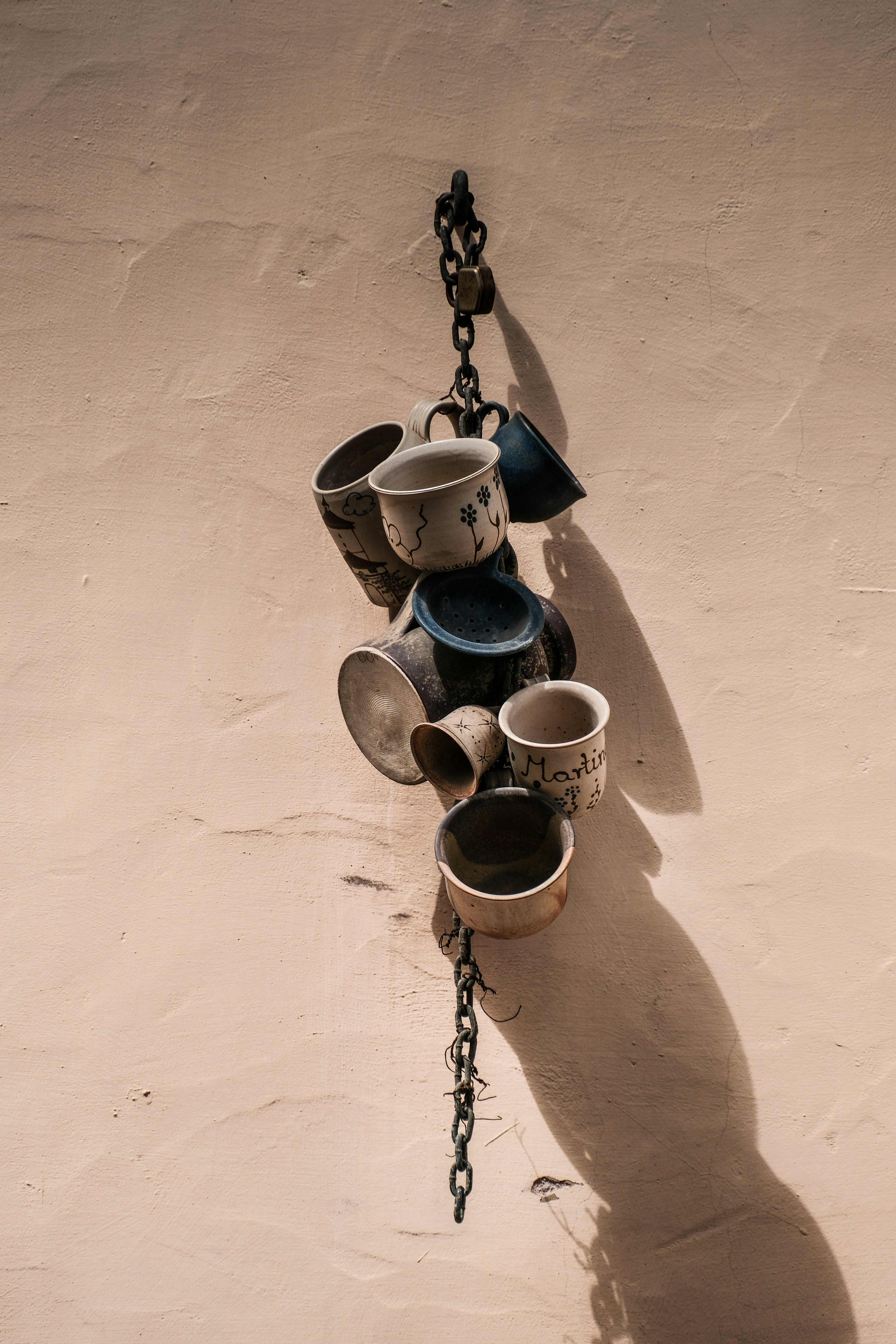 Hanging Echoes: Ceramic Cups Silhouetted Against a Pale Wall