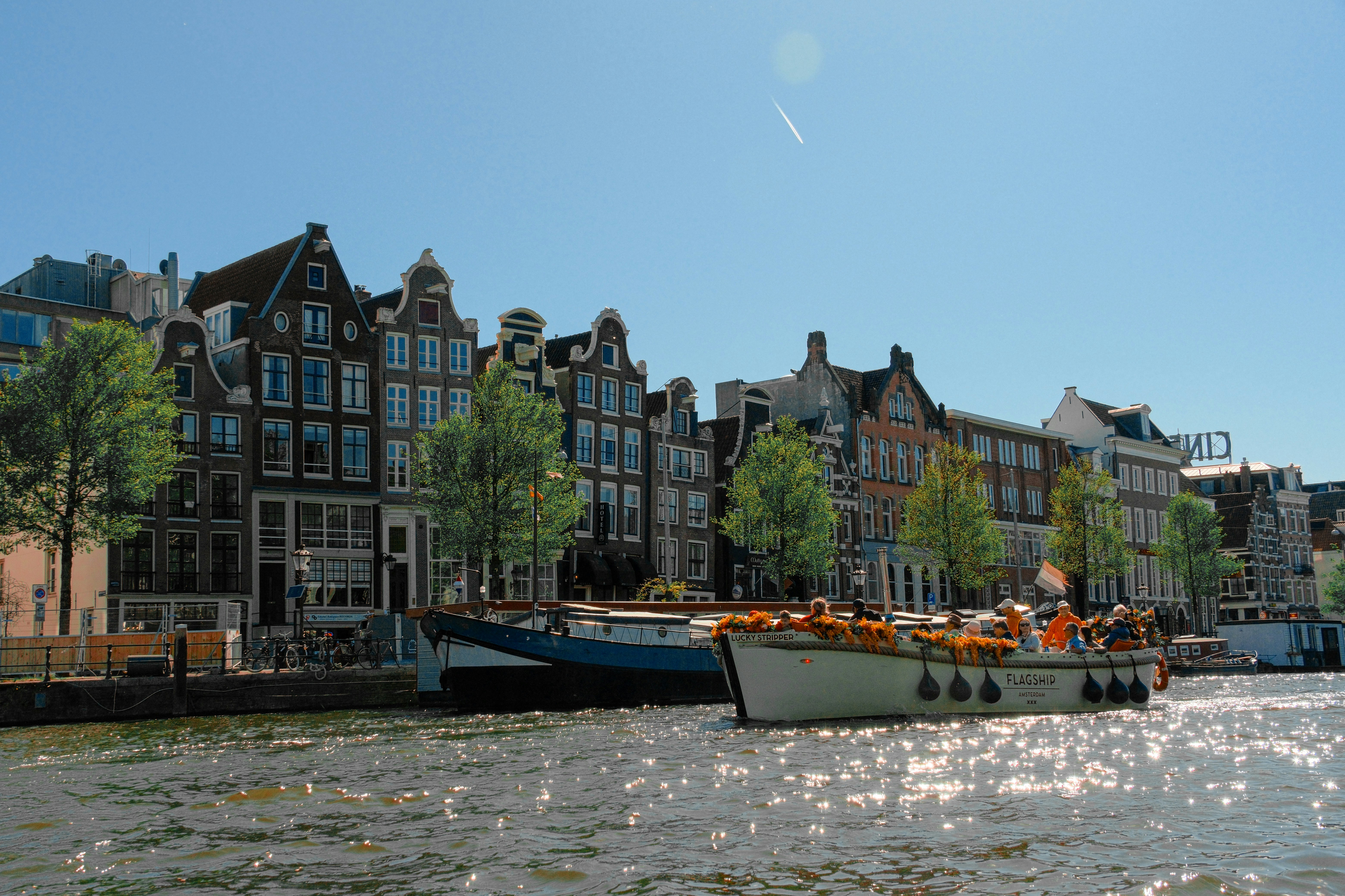 Toward the Canals: A Sunlit Row of Historic Gabled Houses and Floating Boats