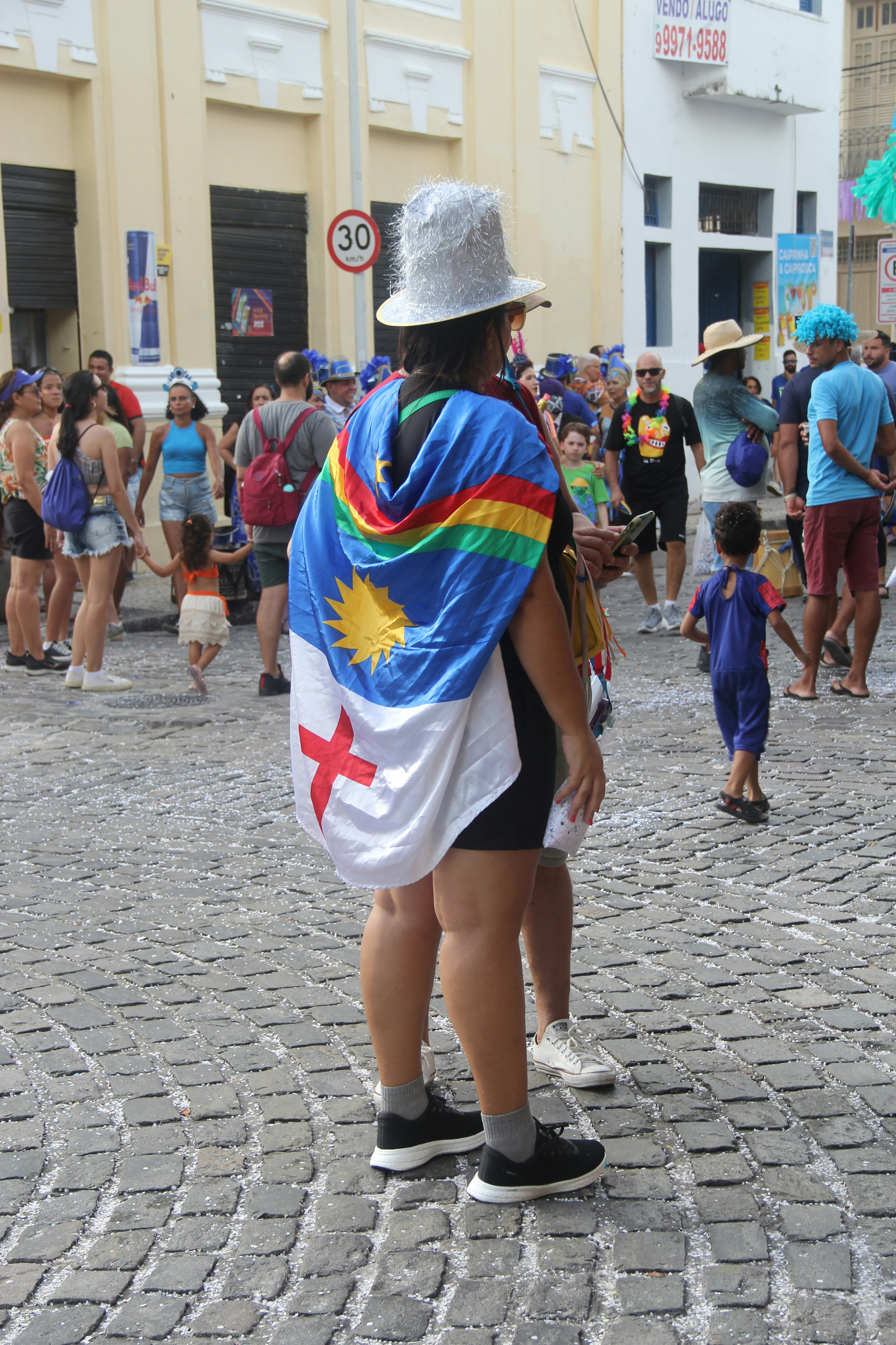 Colorful cape draped over a passing parade participant in a sunny plaza