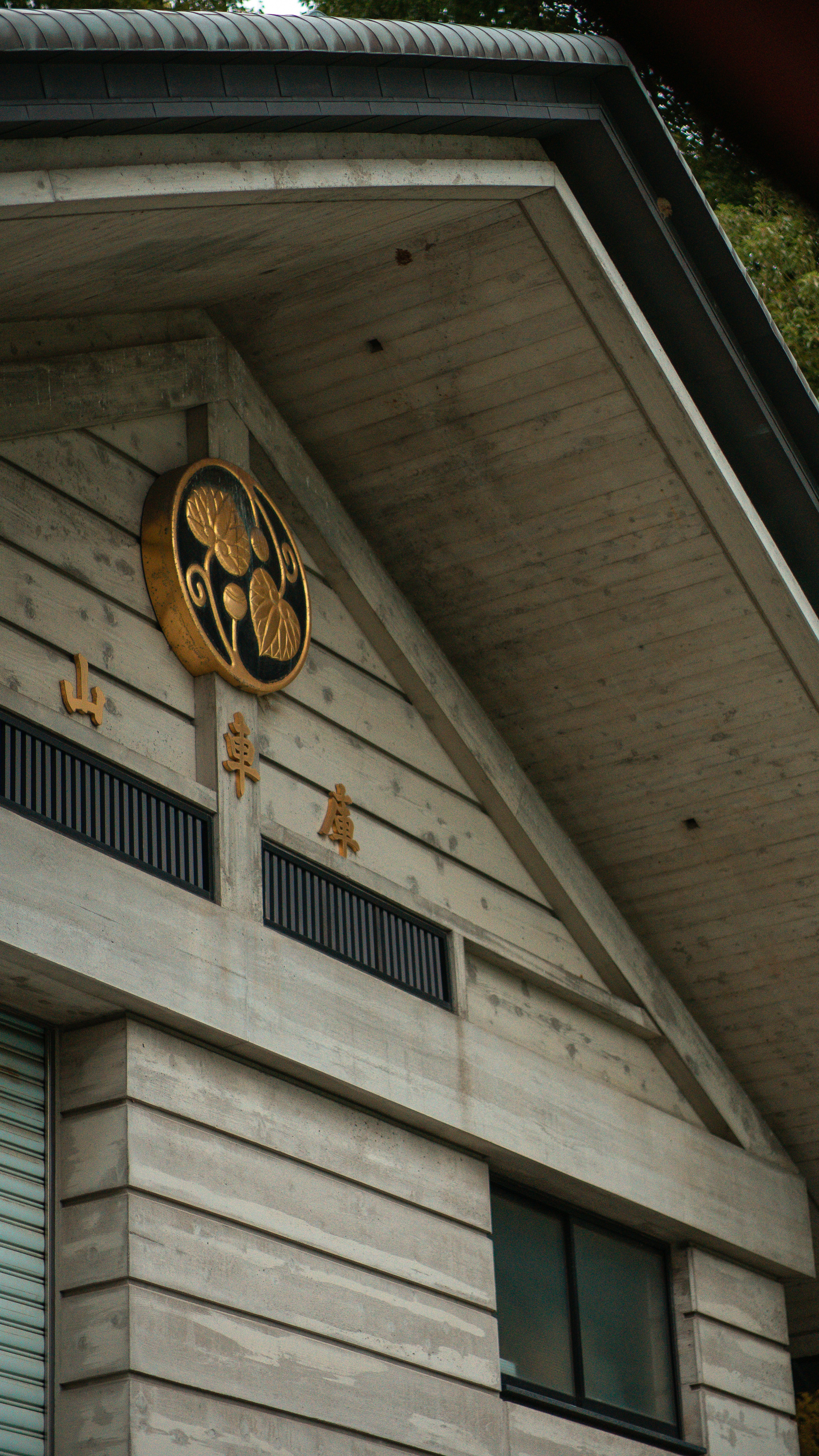 Golden Emblem above Weathered Concrete: A Moment on the Building Facade