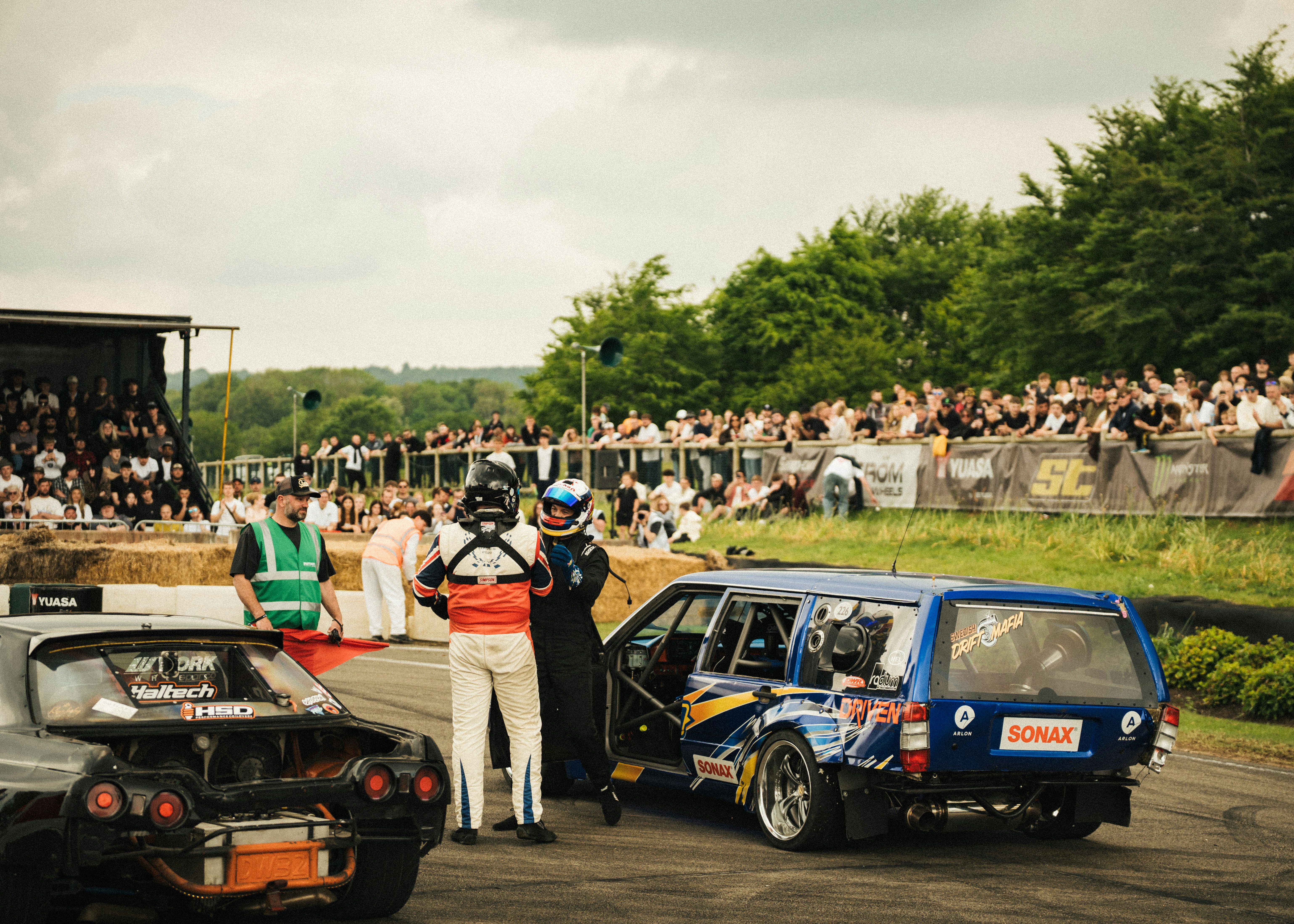 Pit Stop at the Drag Strip: Blue Crossover Car Embraced by Crew and Crowds