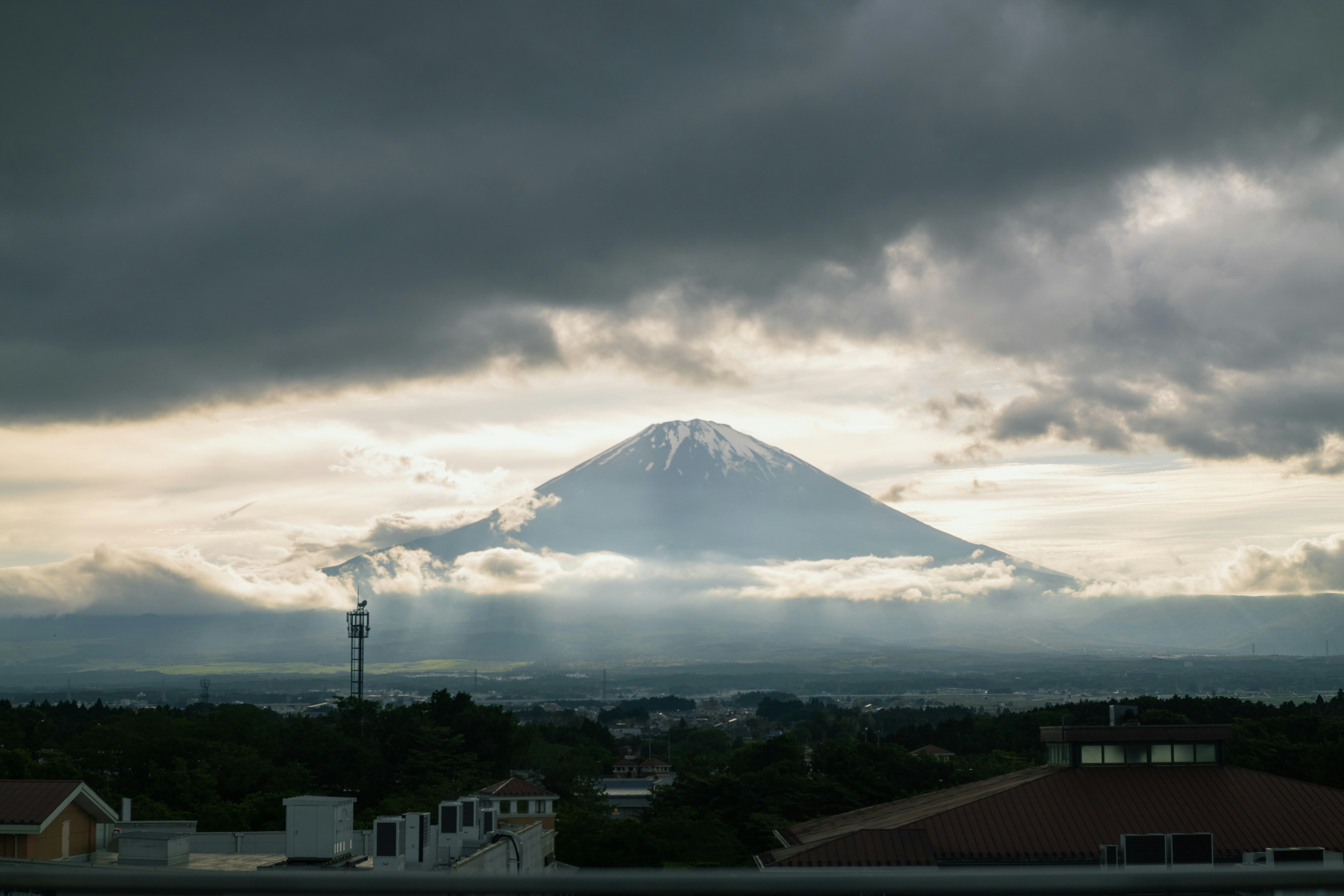Snow-capped Peak Emerging from Low Clouds Over a Quiet Suburban Horizon