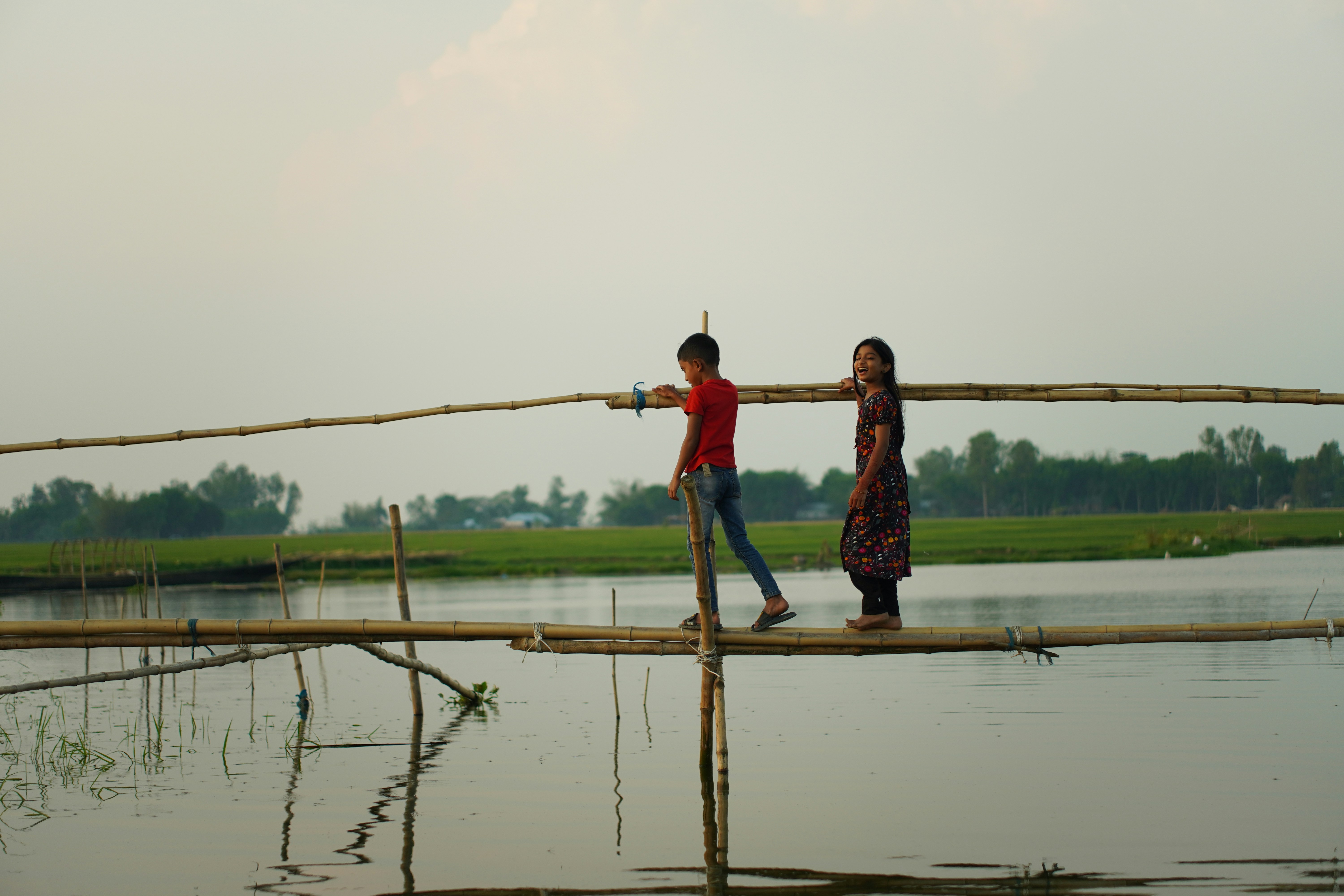 Bridge of Quiet Balance: Two Figures Across a Waterway