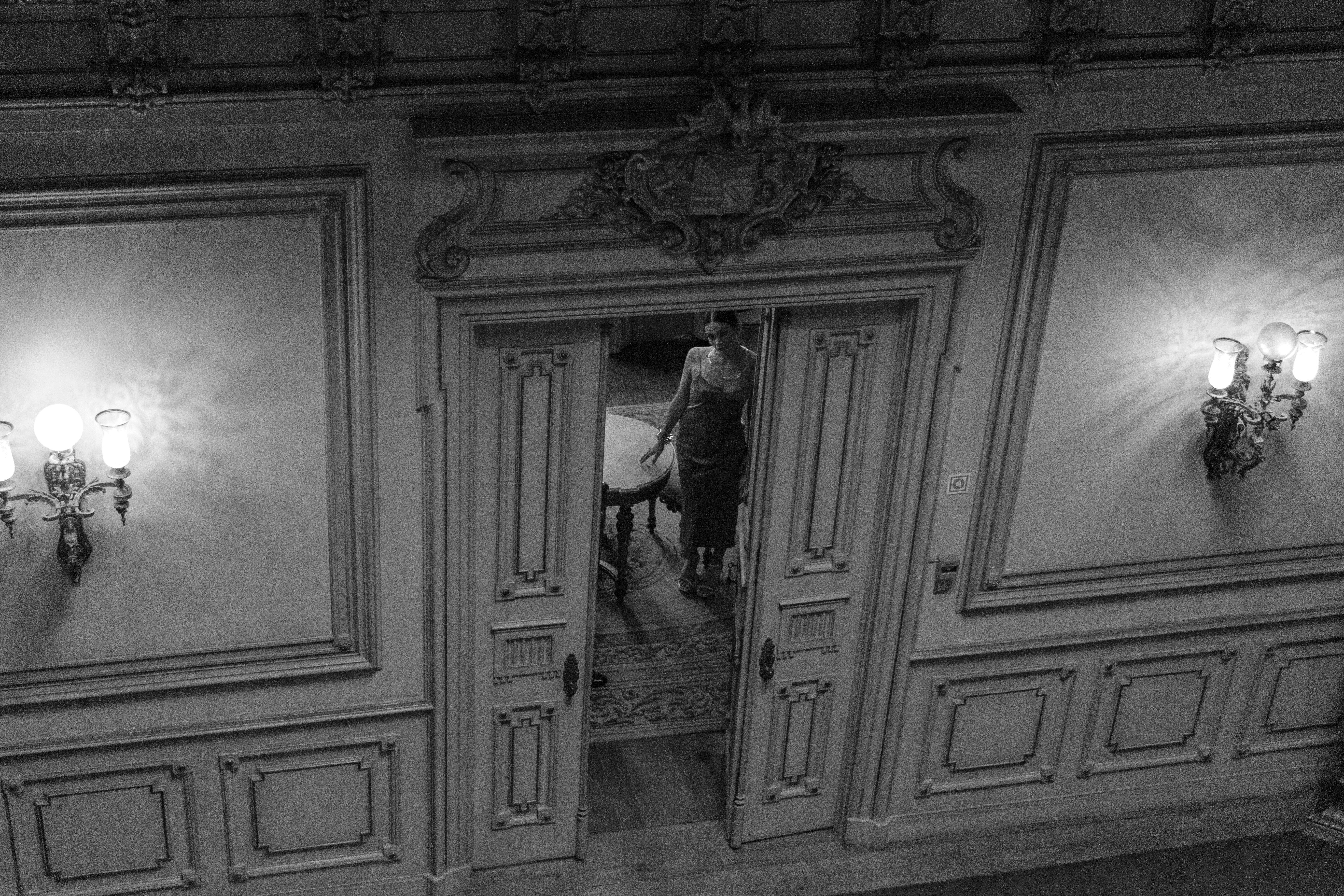 Whispering Doorway: a figure in a vintage hall peeks from the threshold