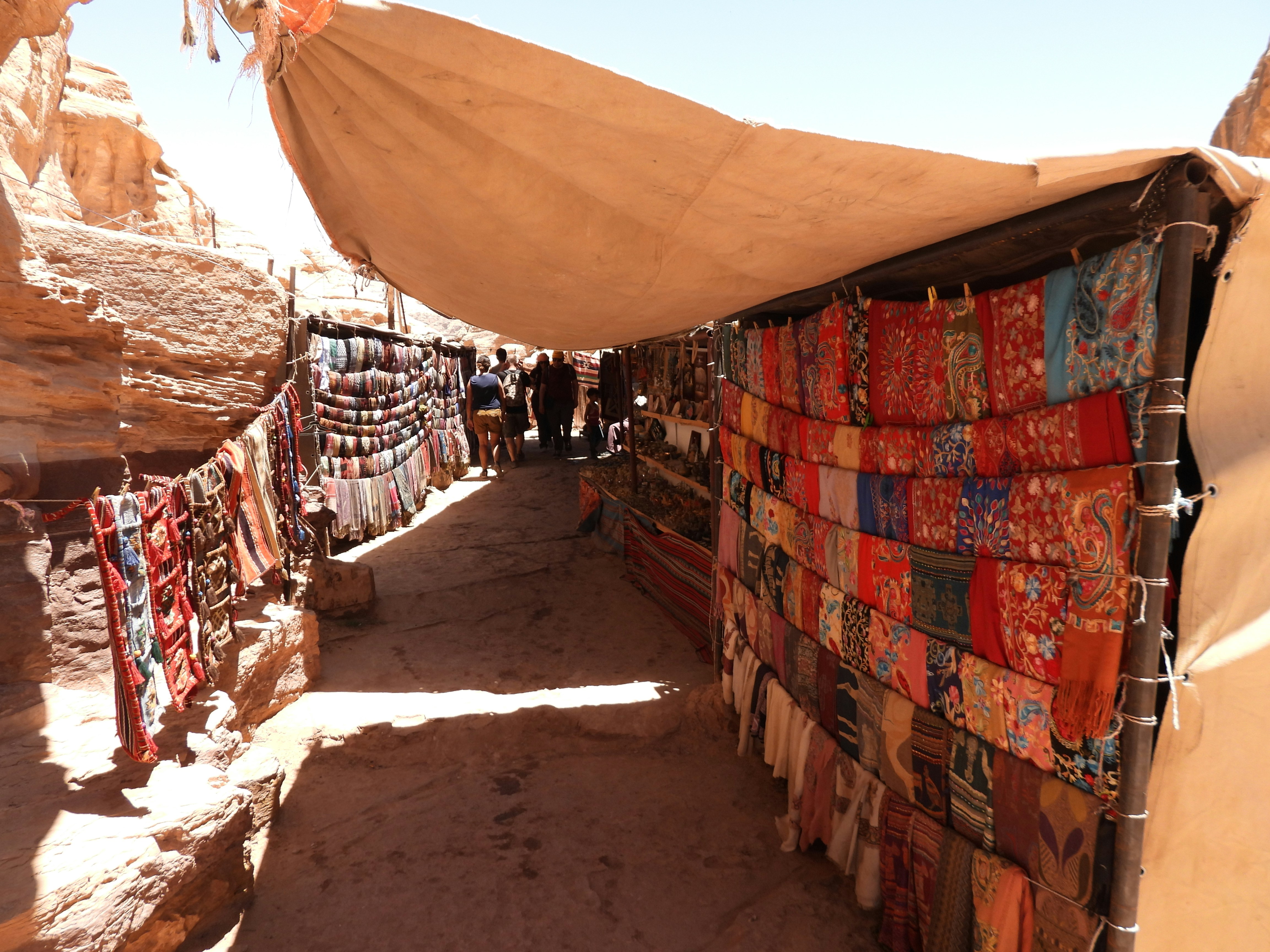 Market Passage: Textiles and Shadows under a Sunlit Canopy