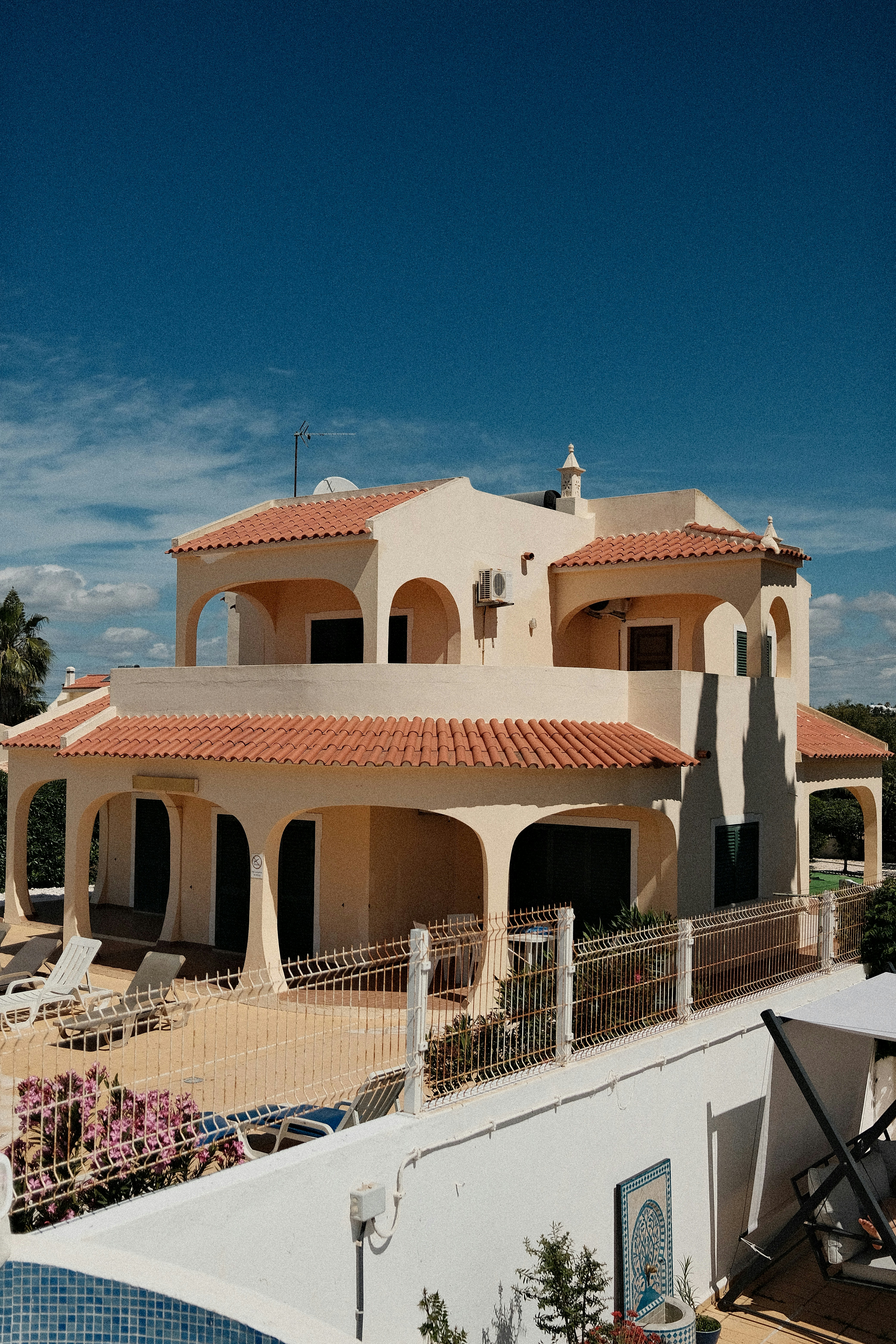 Sunlit Mediterranean Villa: Terracotta Roofs and Archways Under a Clear Sky