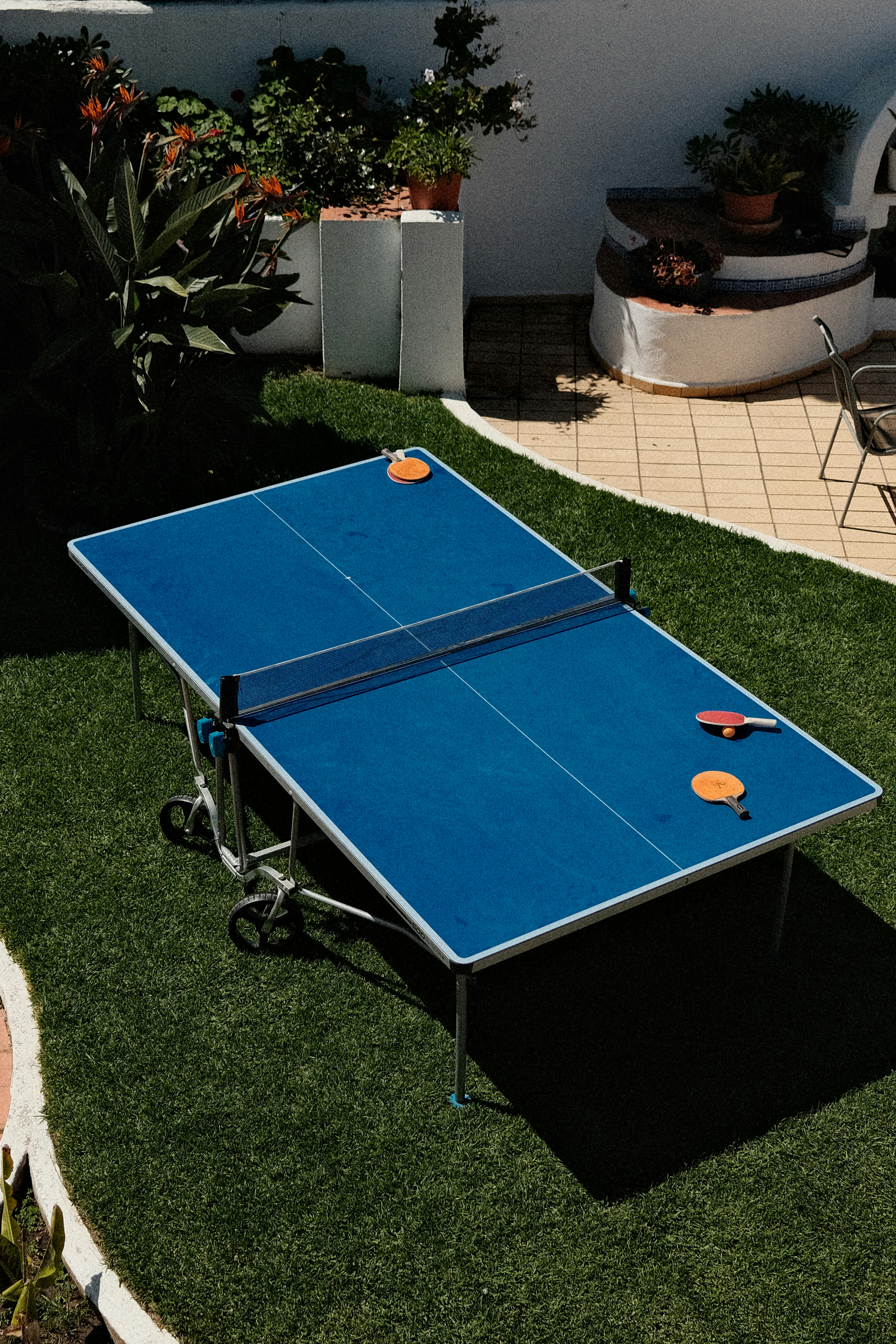 Blue Table Tennis Afloat in Sunlit Courtyard