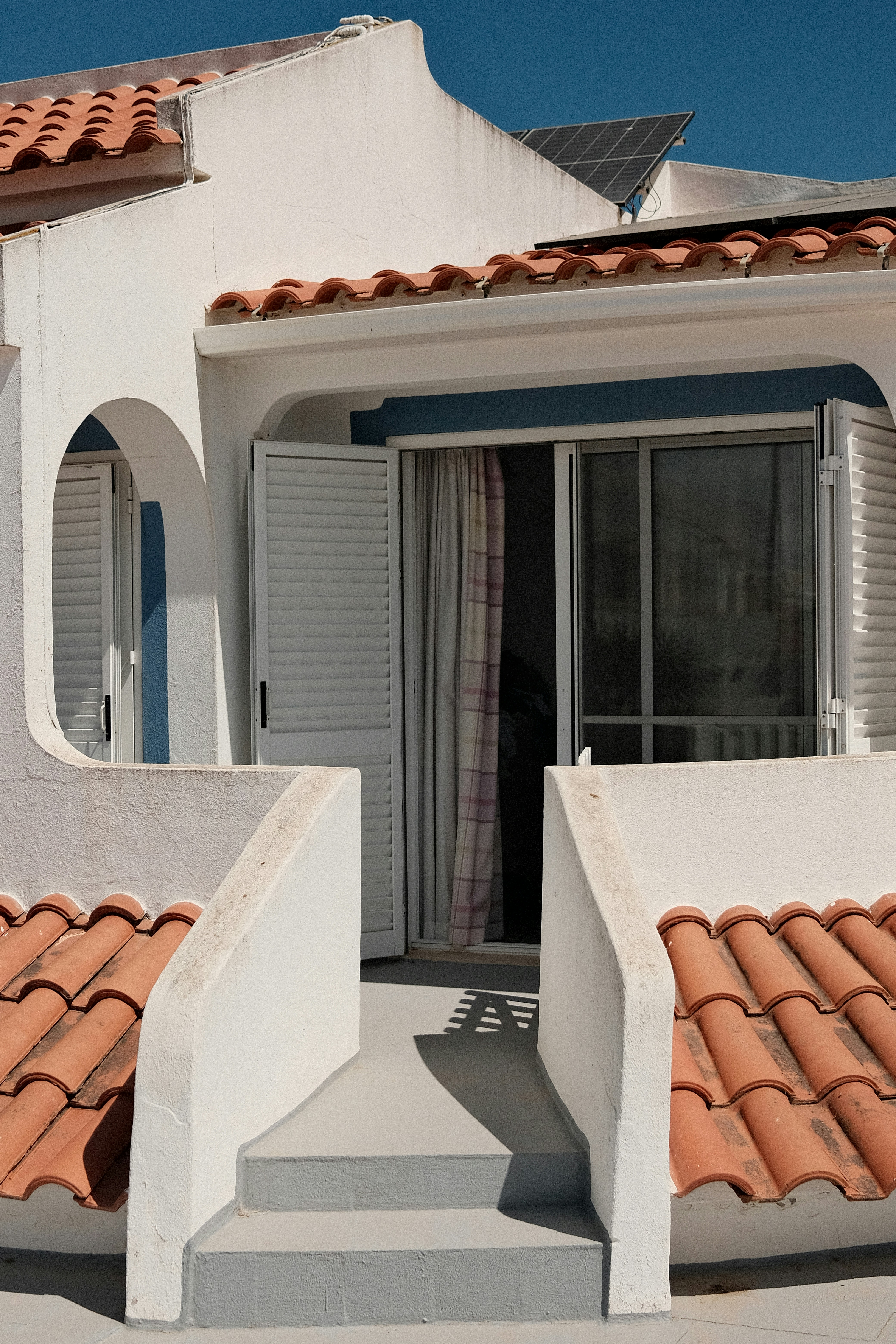 White building with terracotta roof tiles and shutters