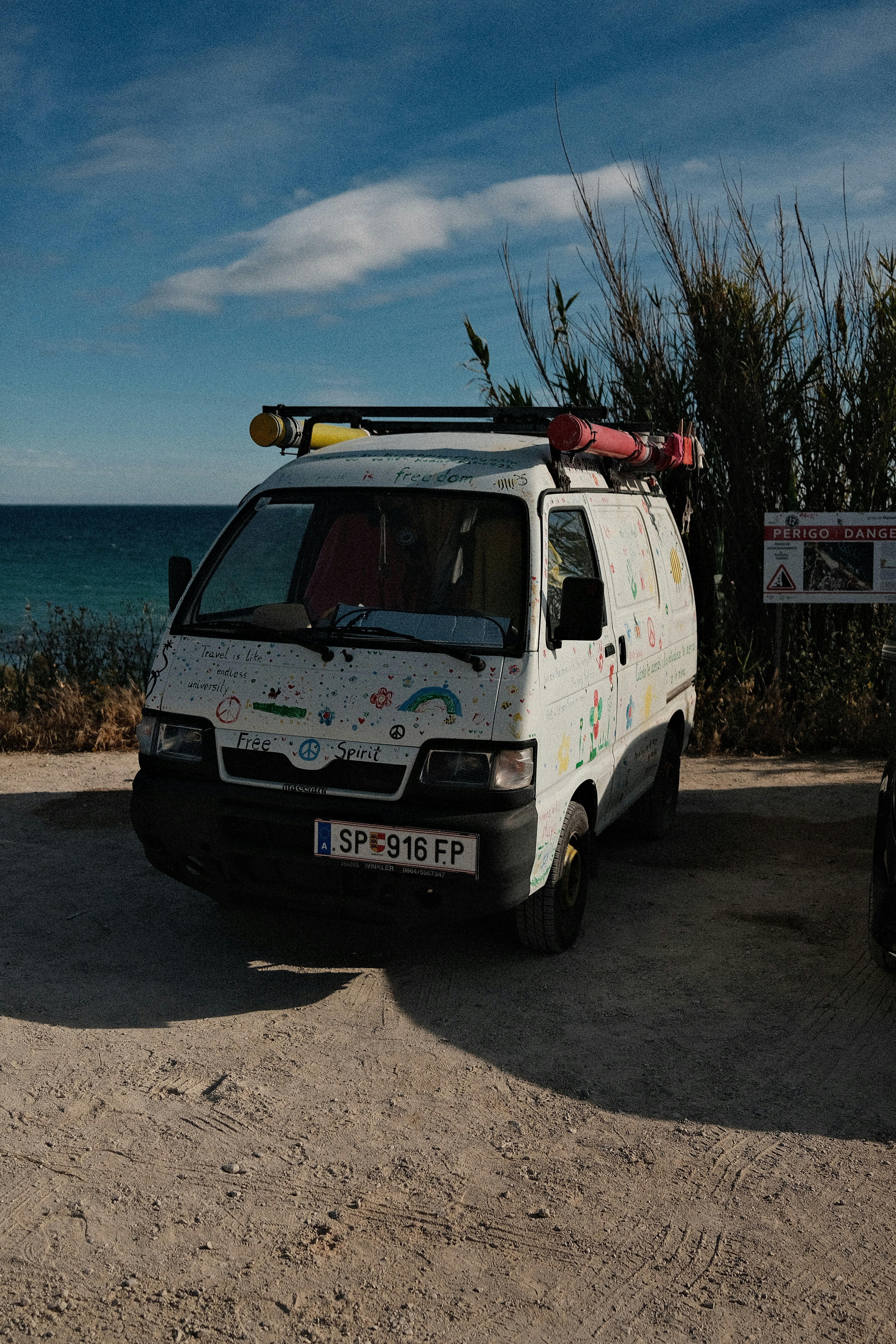 Surfboard-topped van by a coastal lookout