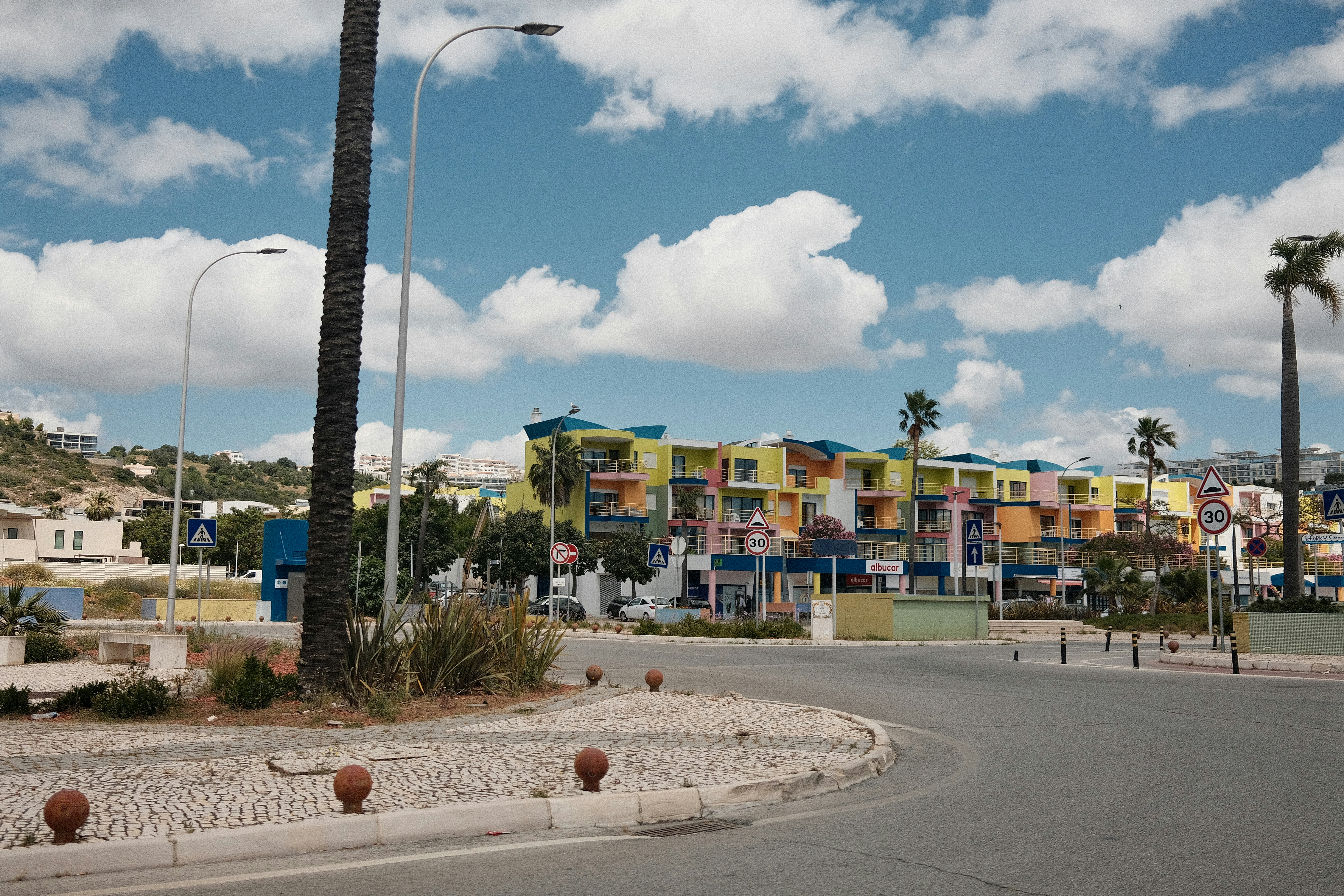 Colorful seaside apartments rise beyond a sunlit roundabout