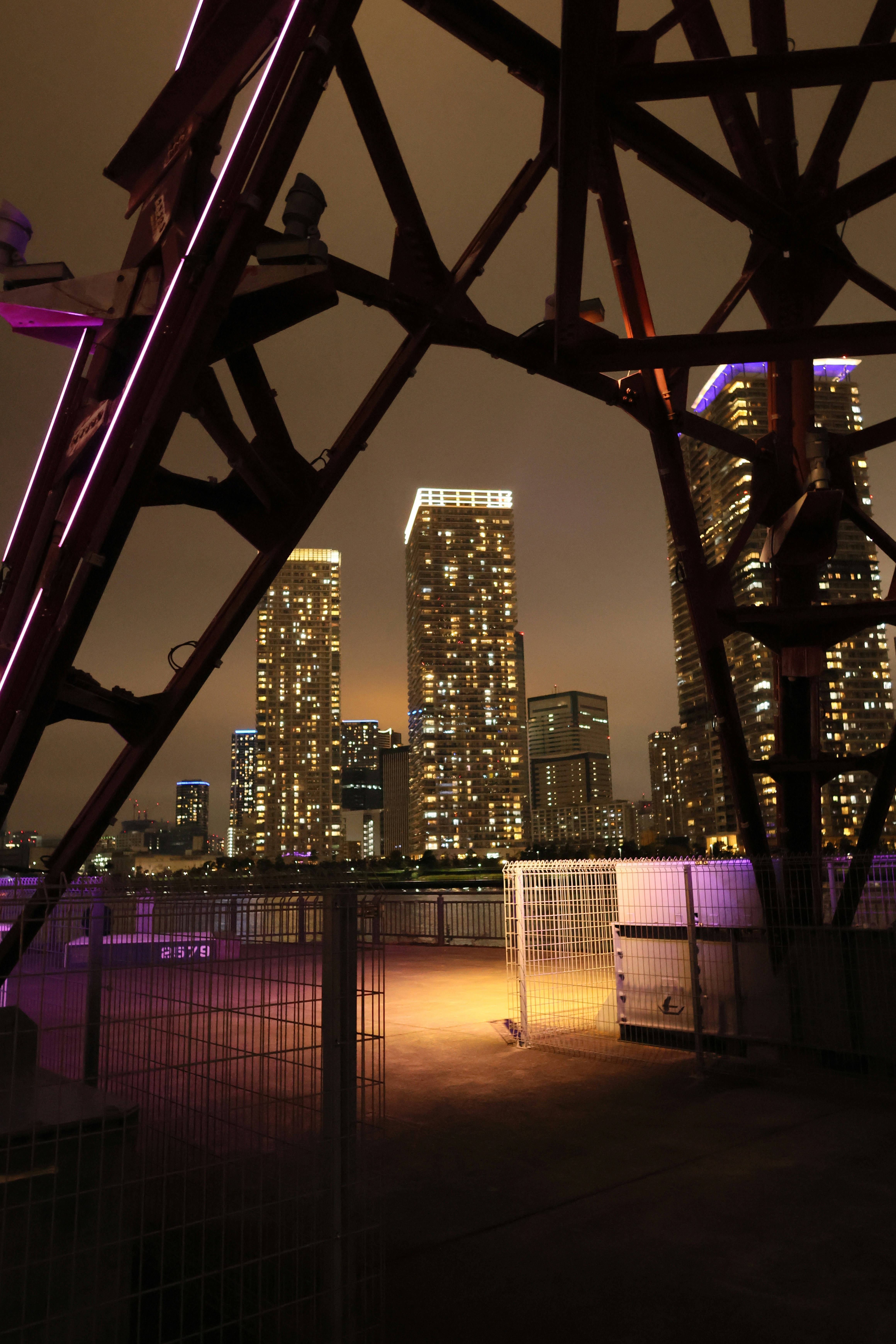 Industrial frame meets city glow: night skyline through lattice shadows