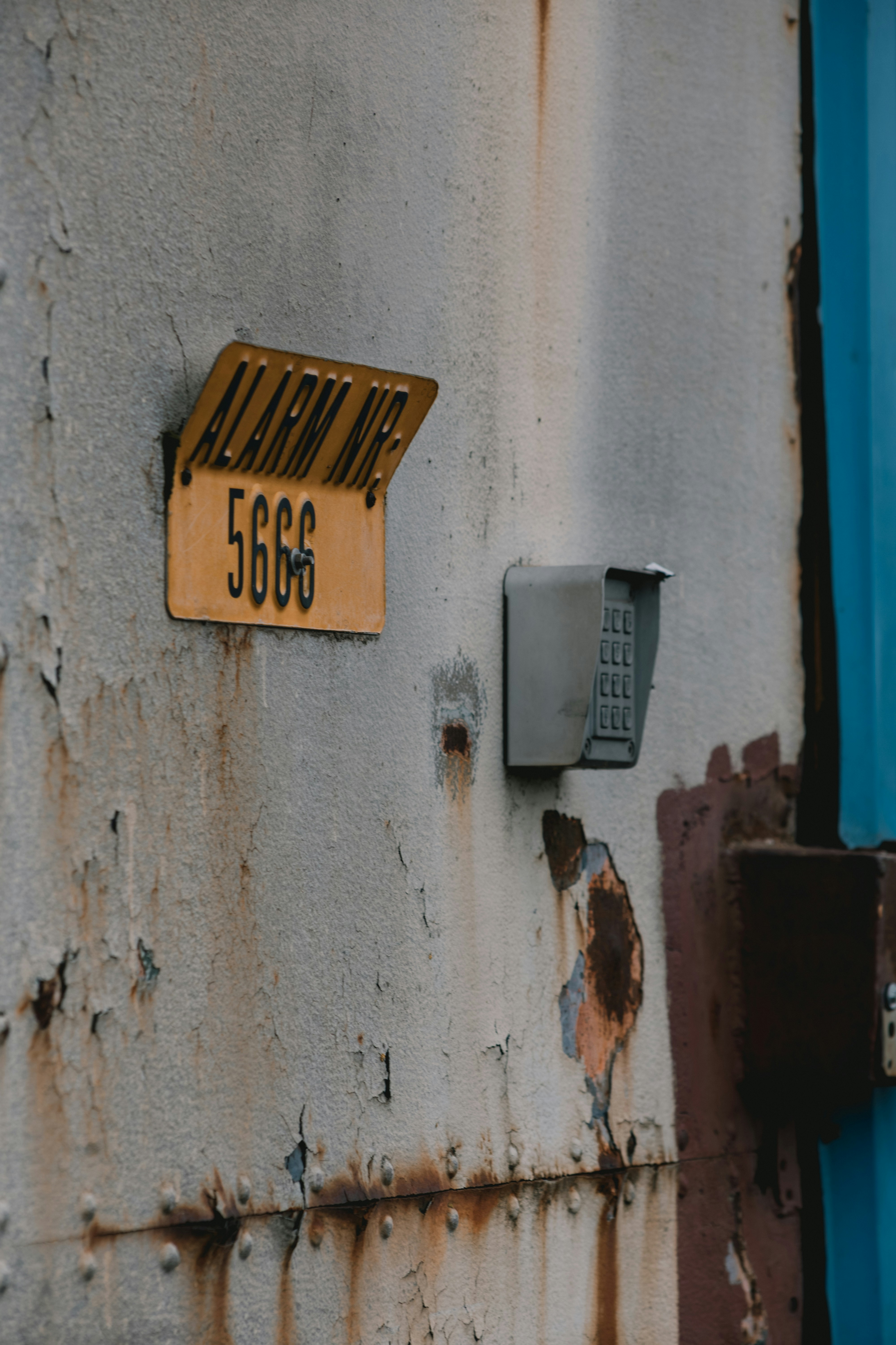 Weathered Doorway: A Rusted Plaque and Industrial Panel on a Cracked Wall