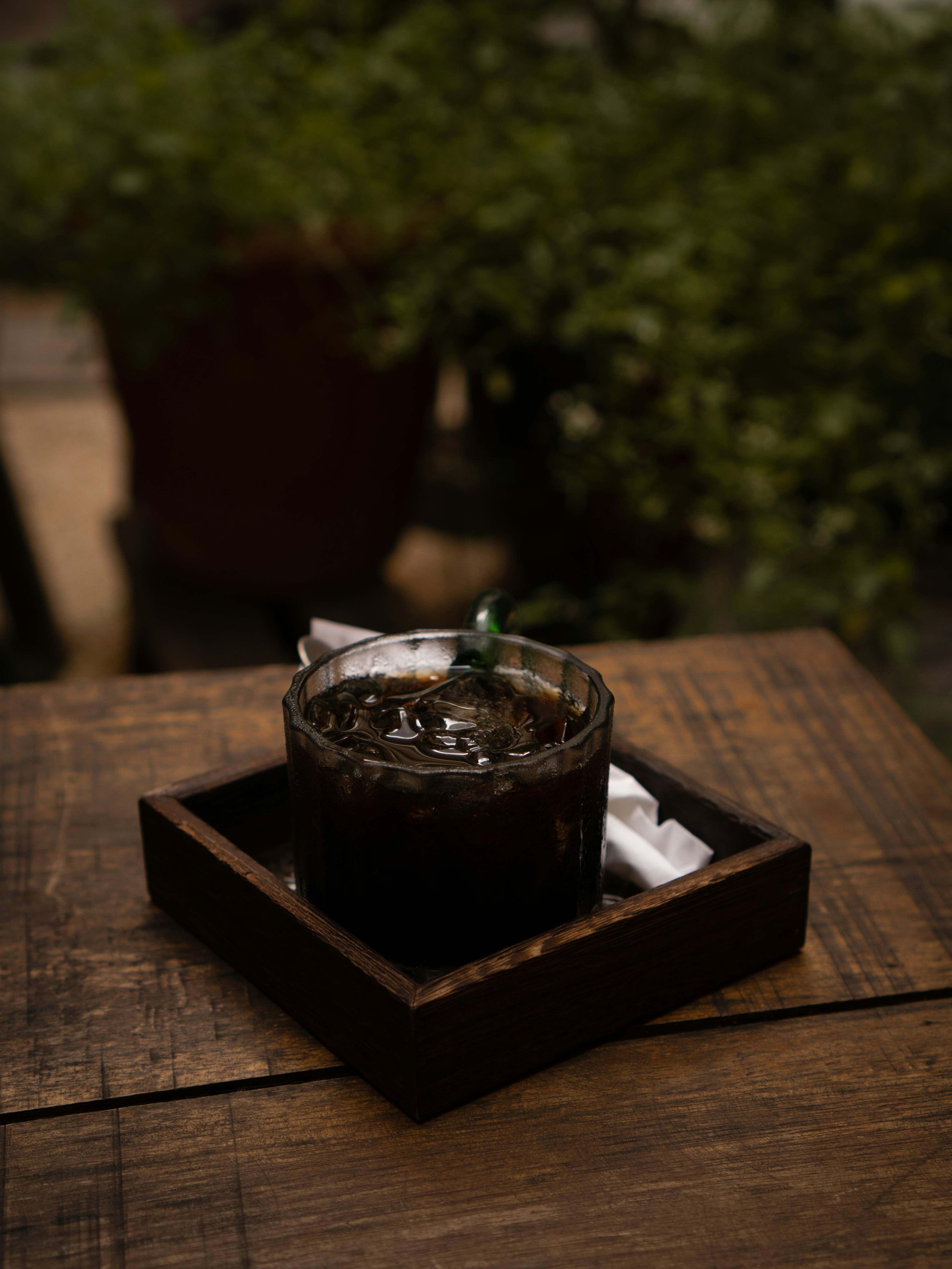 Glass of cola on a weathered table in soft outdoor light