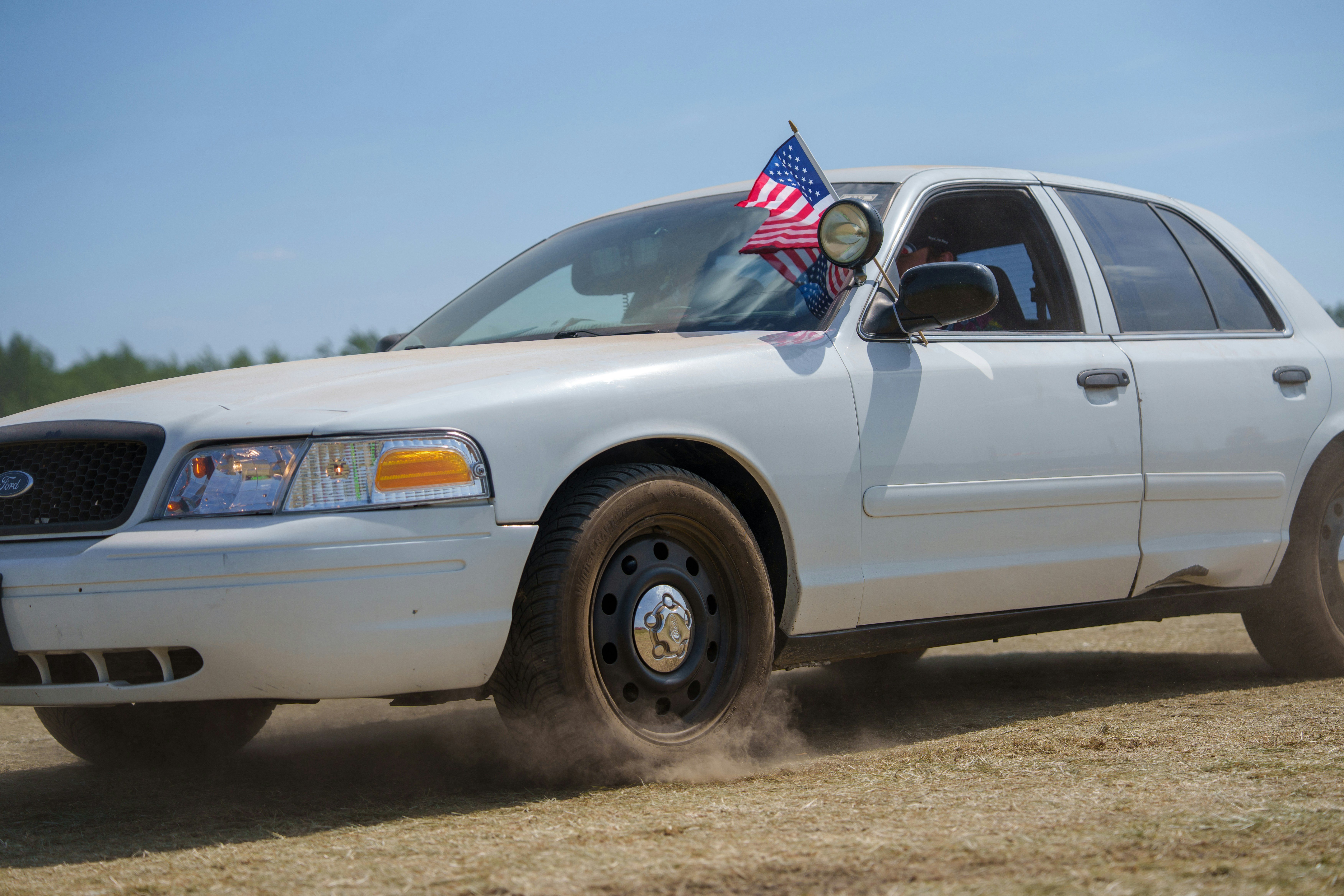 Flag on the Pursuit: A Patrol Sedan Kicking Up Dust