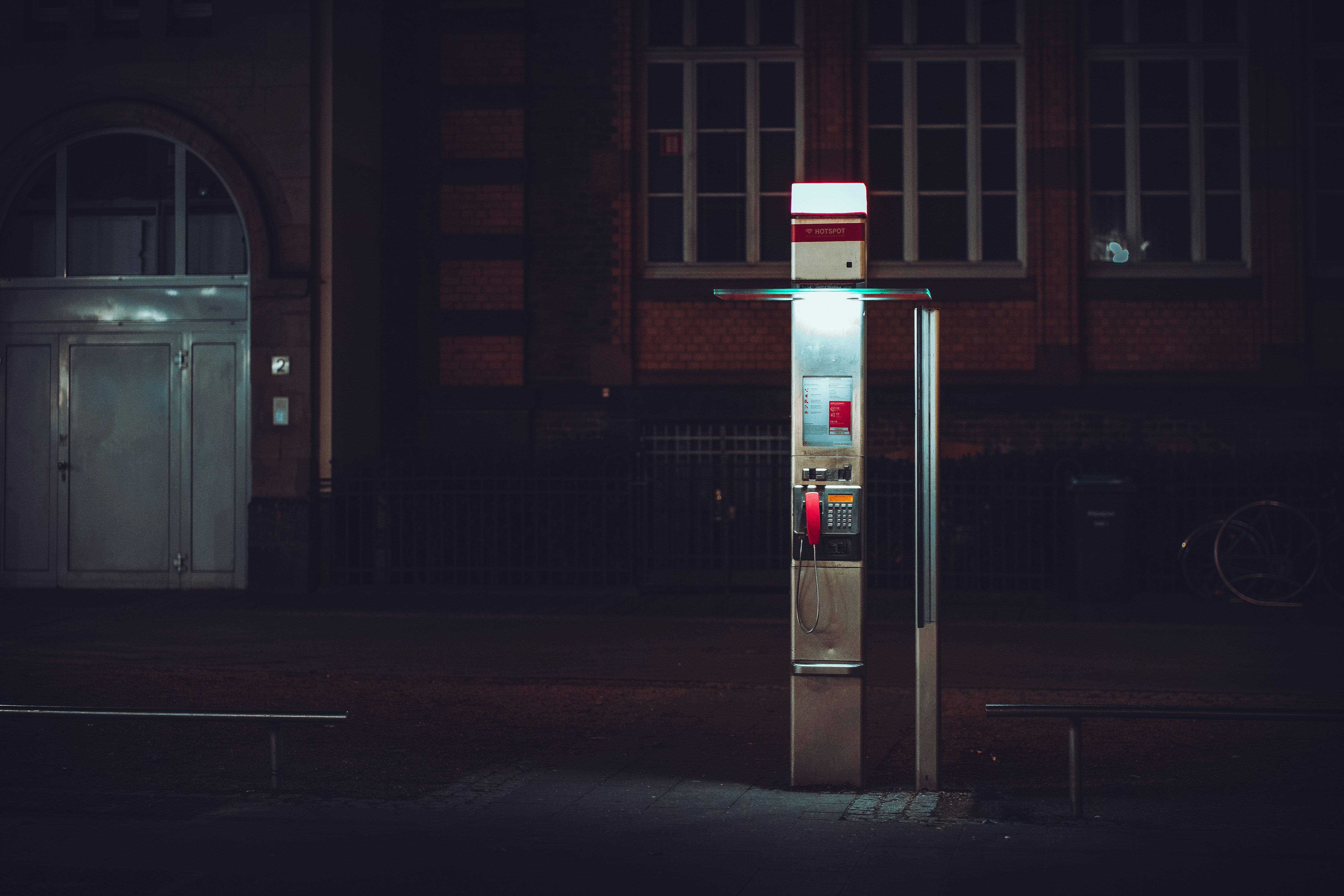 Midnight Pillar: A lone payphone glows beneath a quiet urban facade