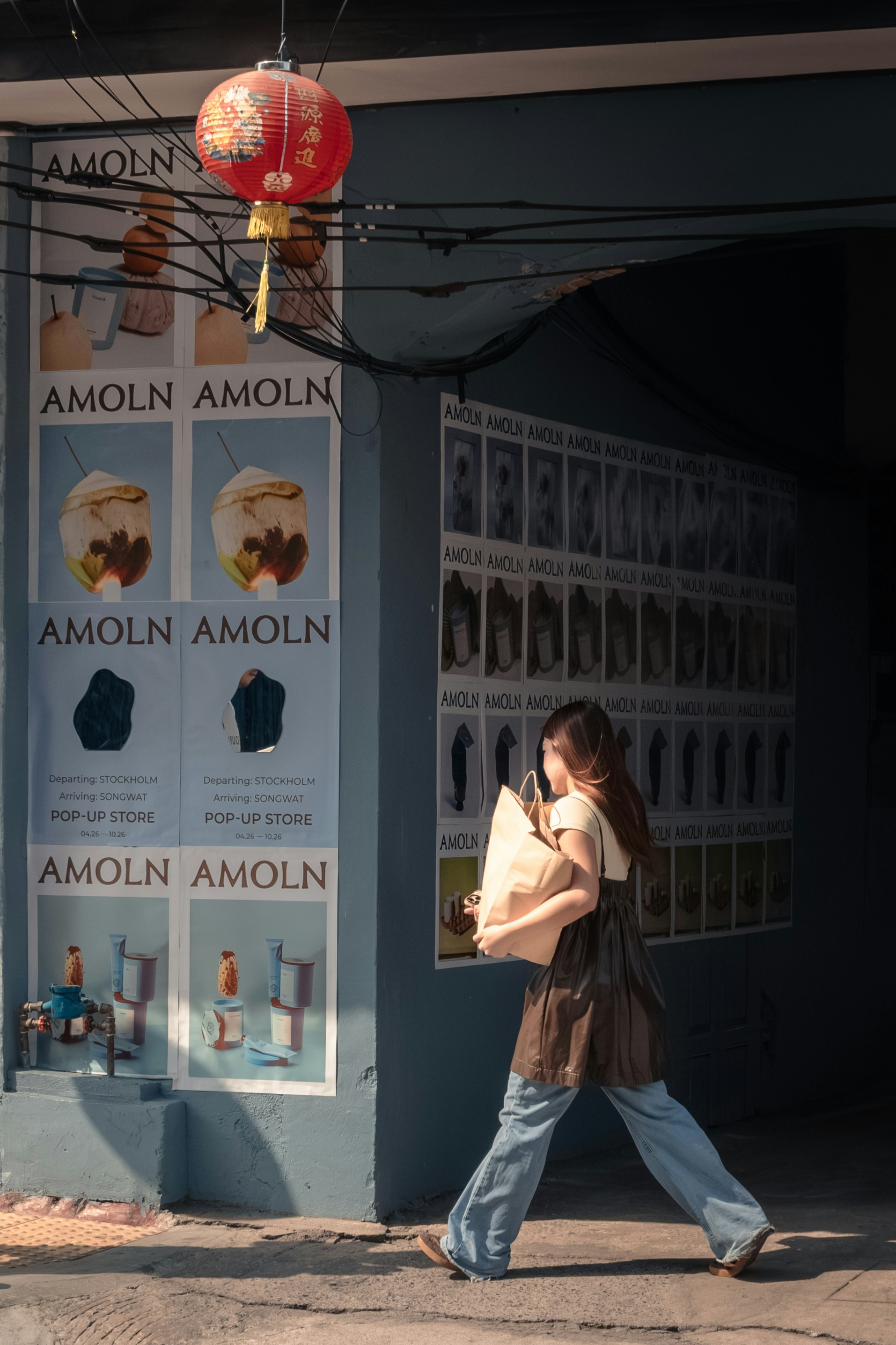 Sunlit Stride past a Neon-Blue Wall of Posters