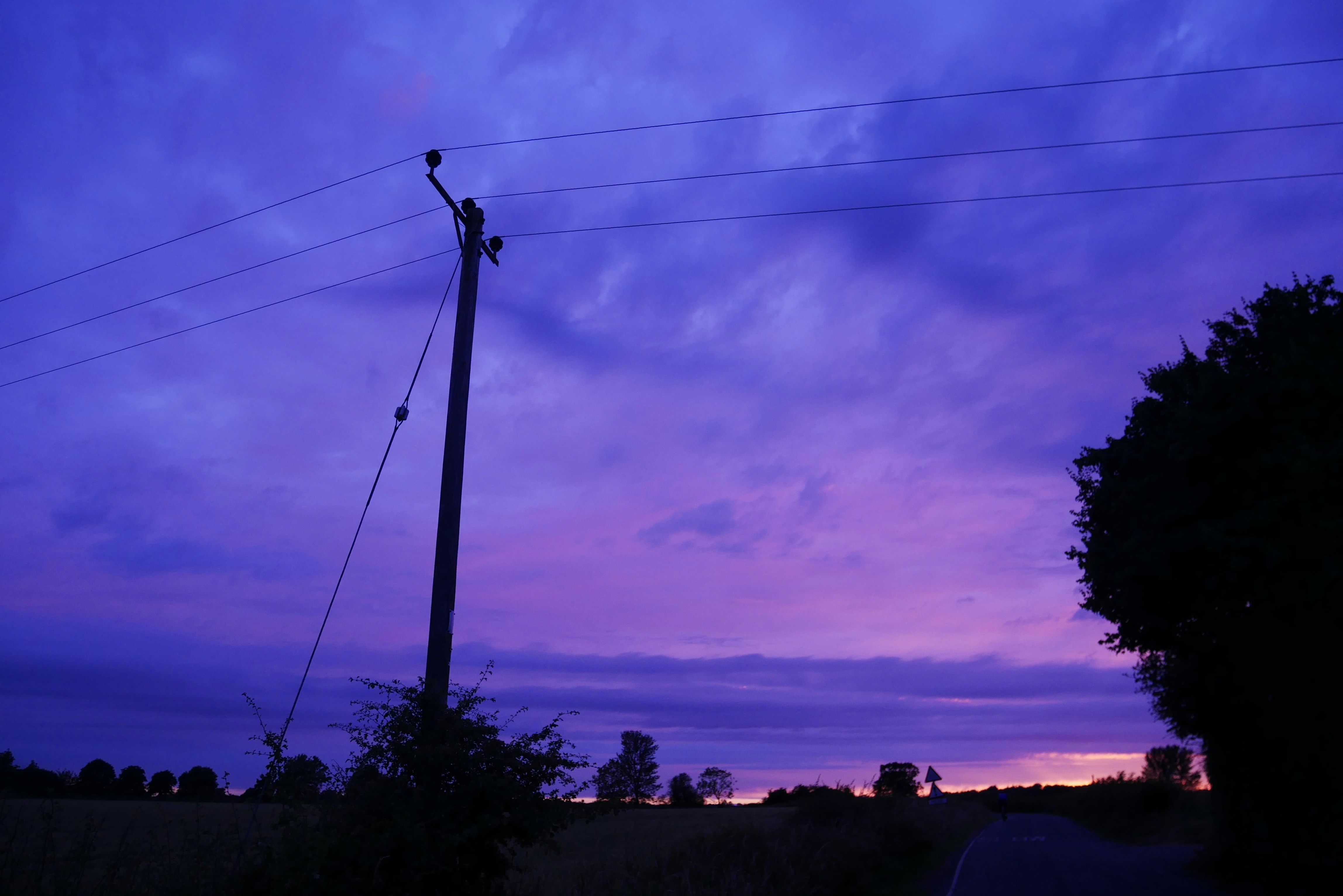 Silhouetted utility pole at dusk over a horizon of purple skies