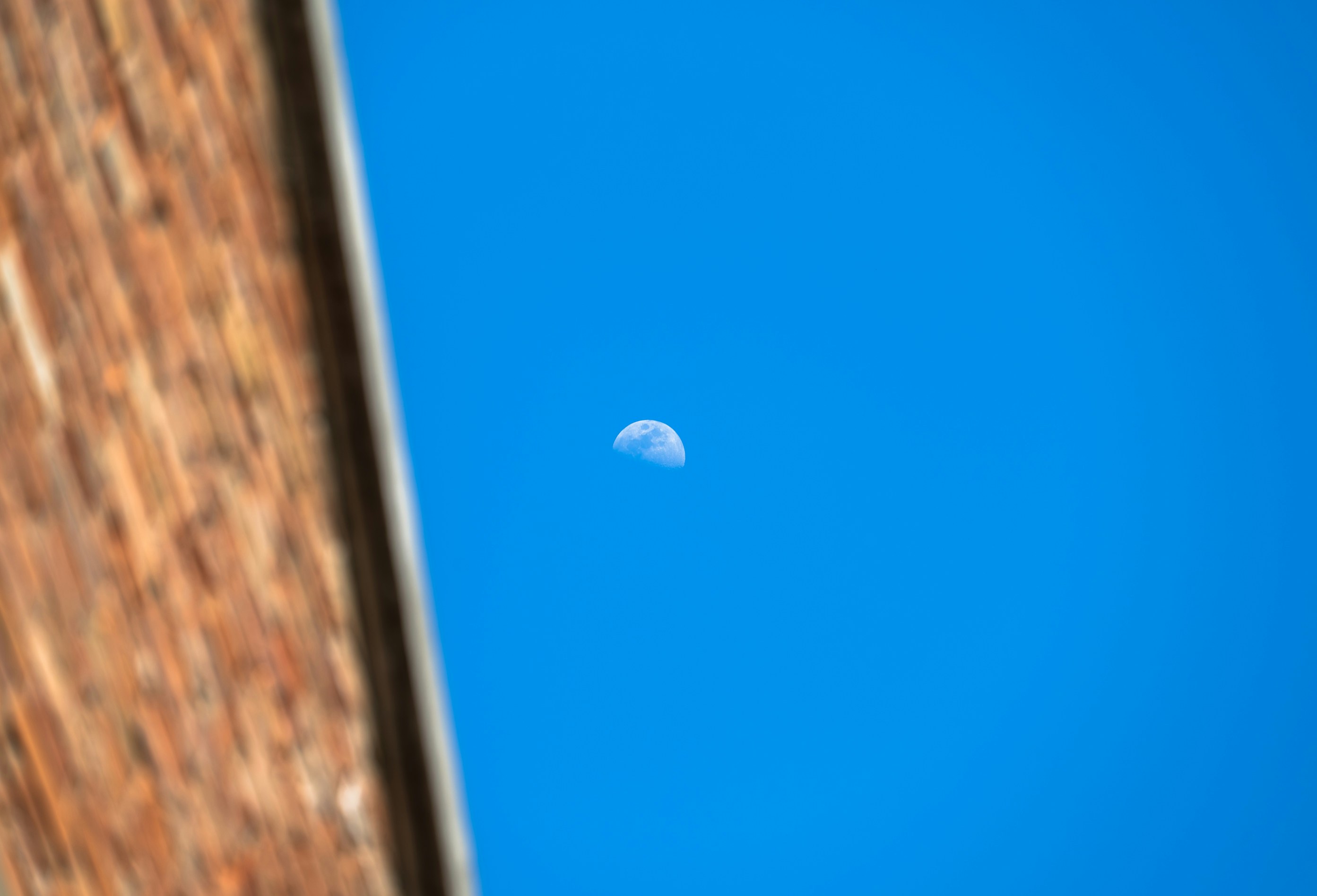 Moon in a Clear Blue Sky Framed by Brick Sides