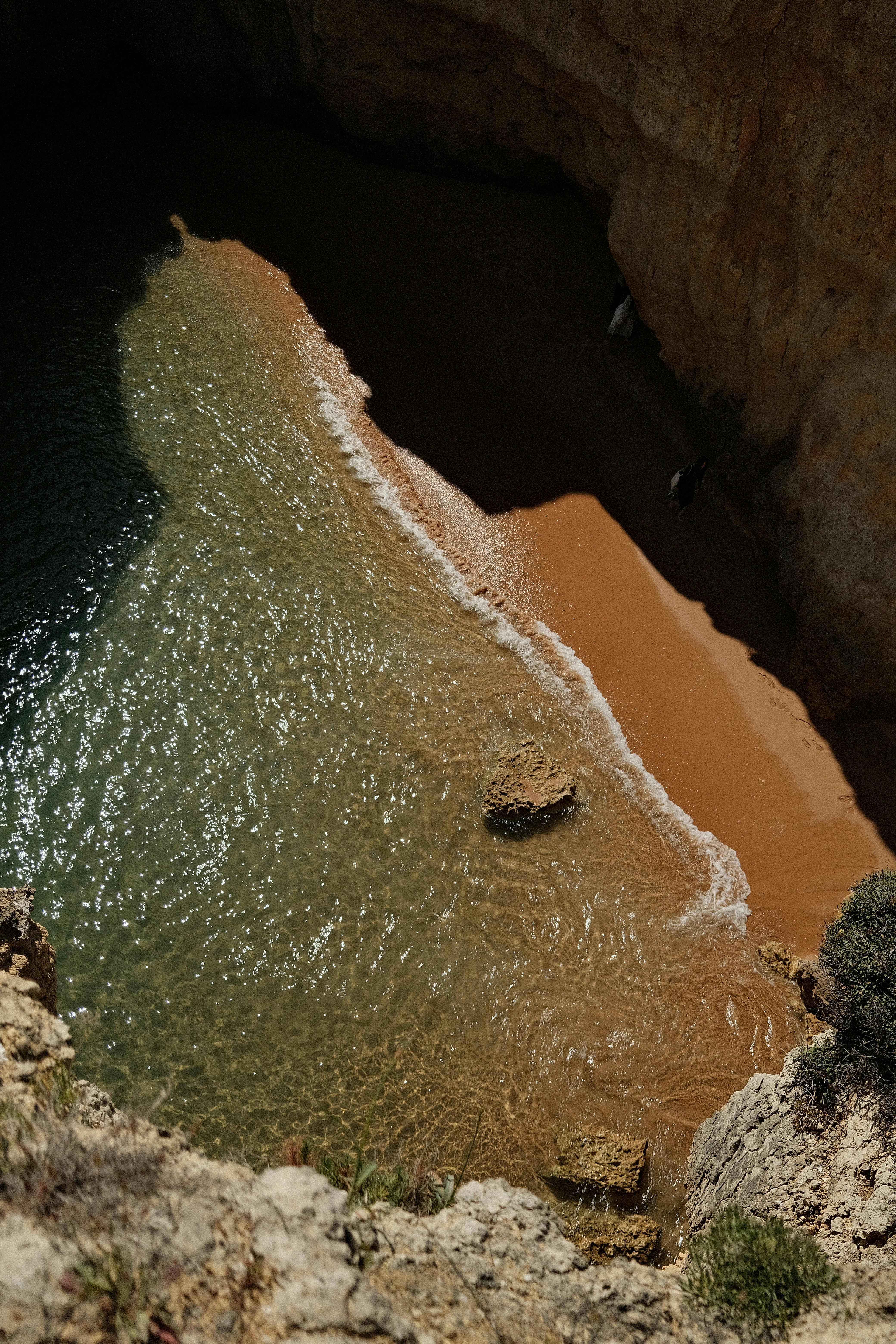 A Hidden Cove: Sunlit Beach Enclosed by Cliffside Shadows