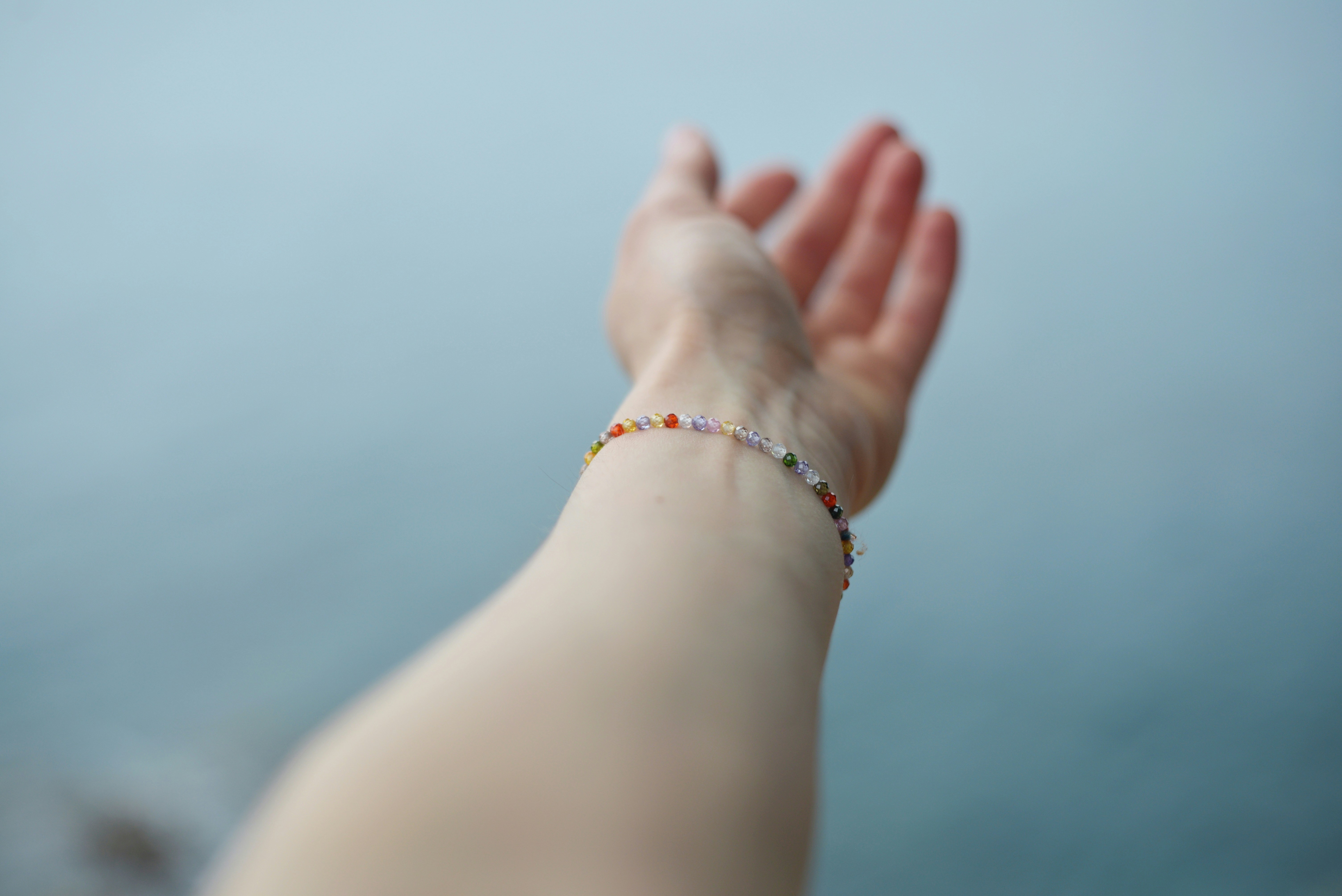 Outstretched Moment: A Pearl Bracelet Reaches Toward the Sea