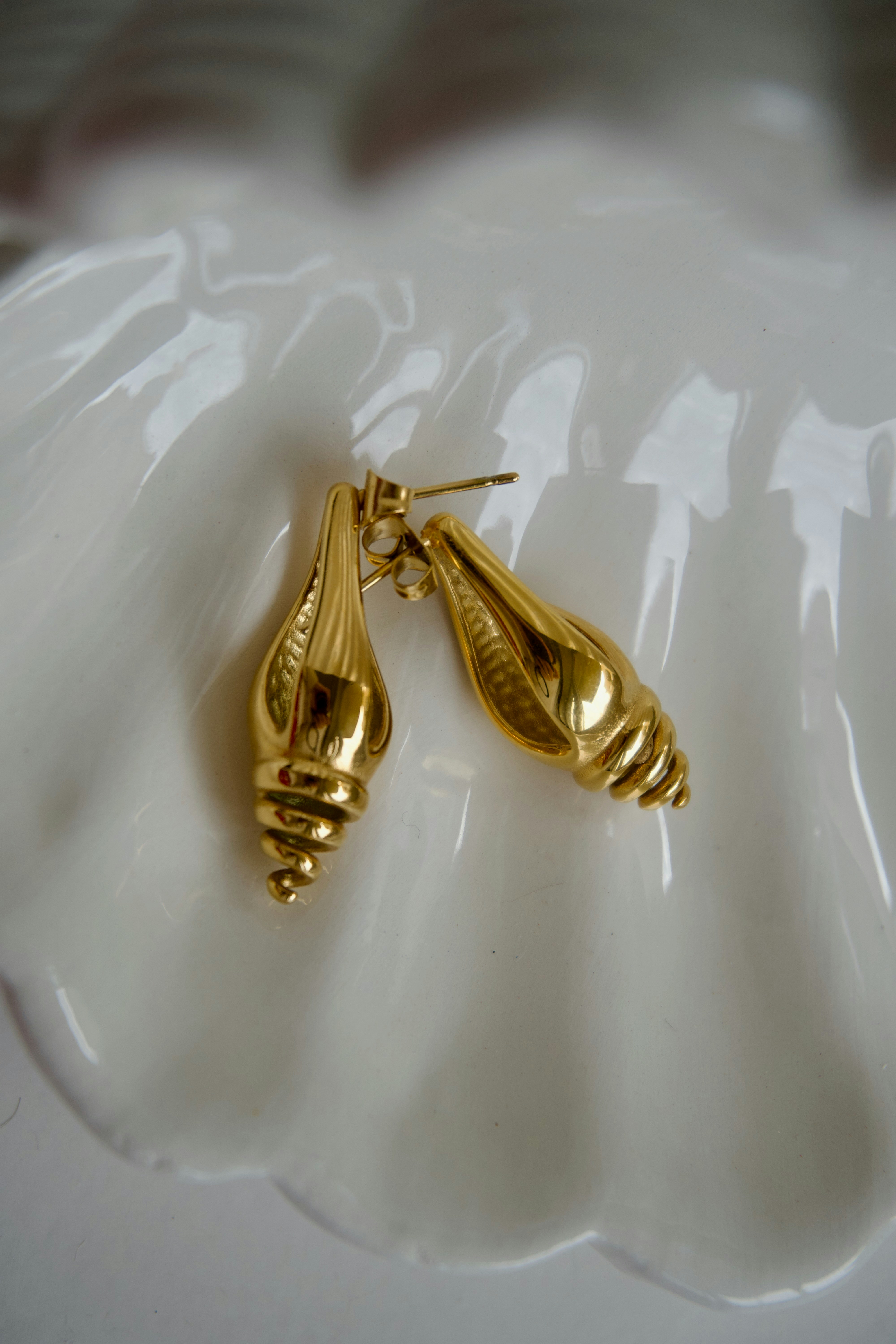 Golden Spirals: Earrings Resting on a Soft White Surface
