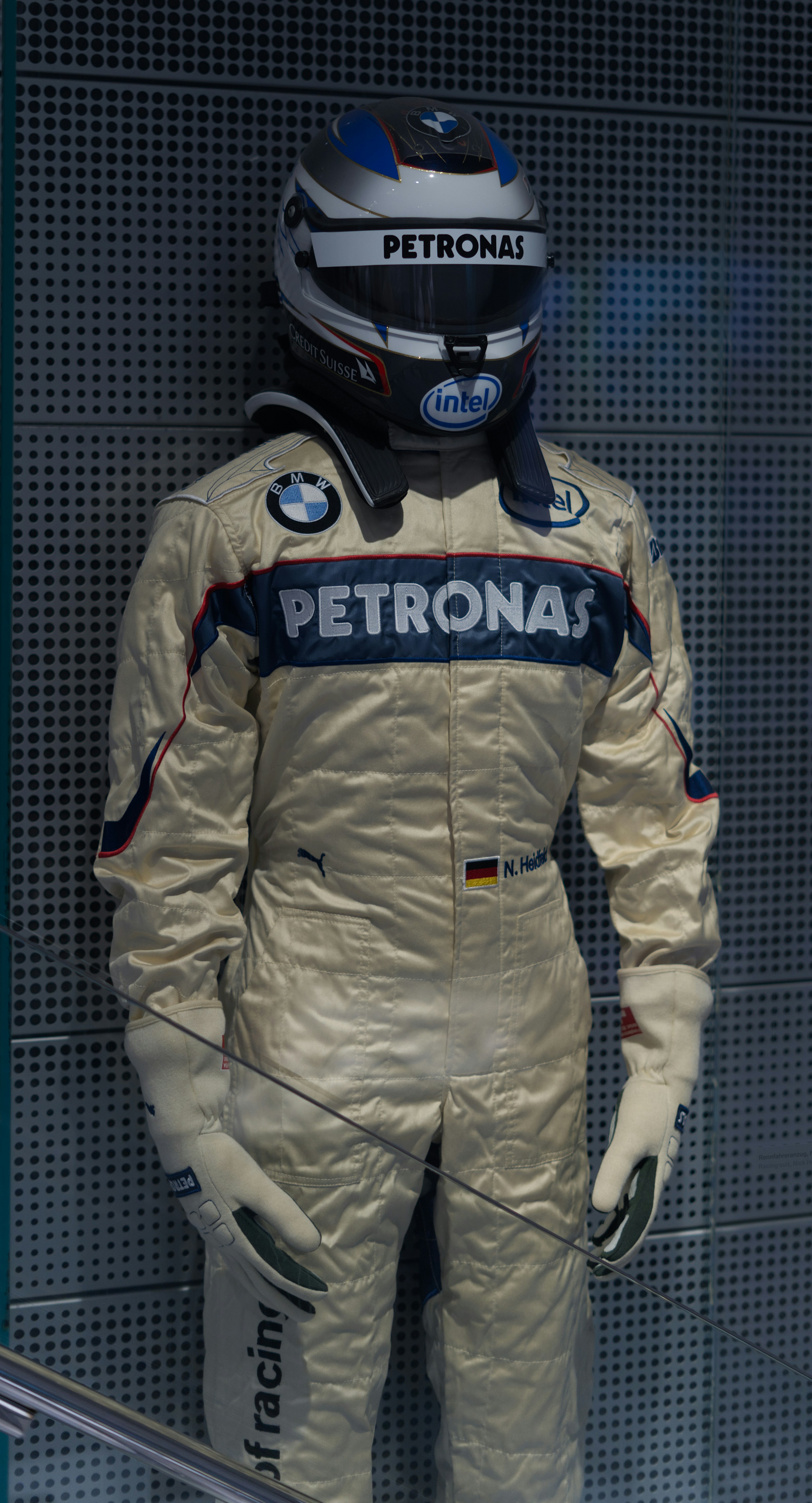Petronas Racing Suit: Helmeted Precision in Metal Grille Backdrop
