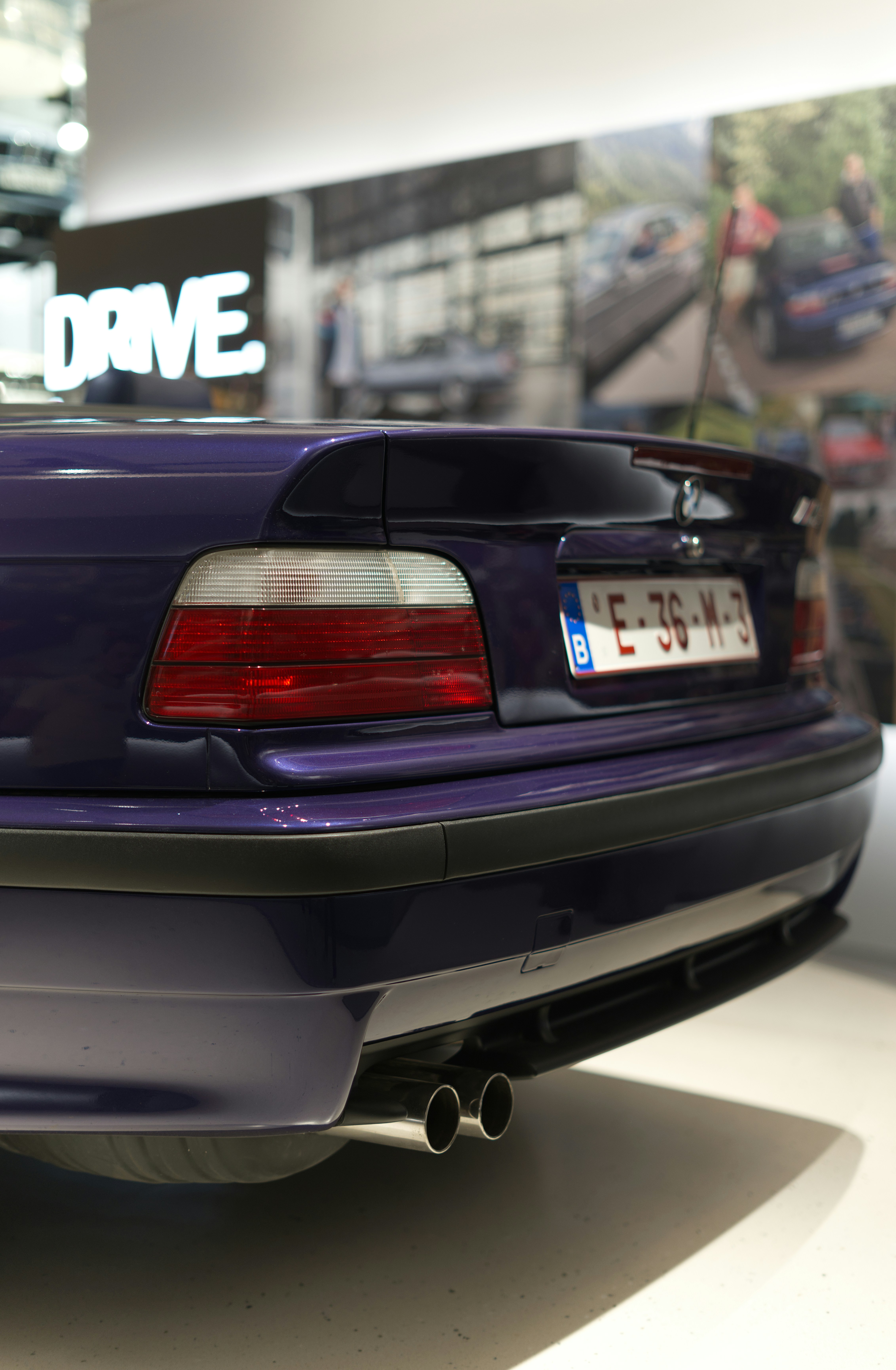 Purple coupe at the showroom exit, exhaust pipes in soft focus