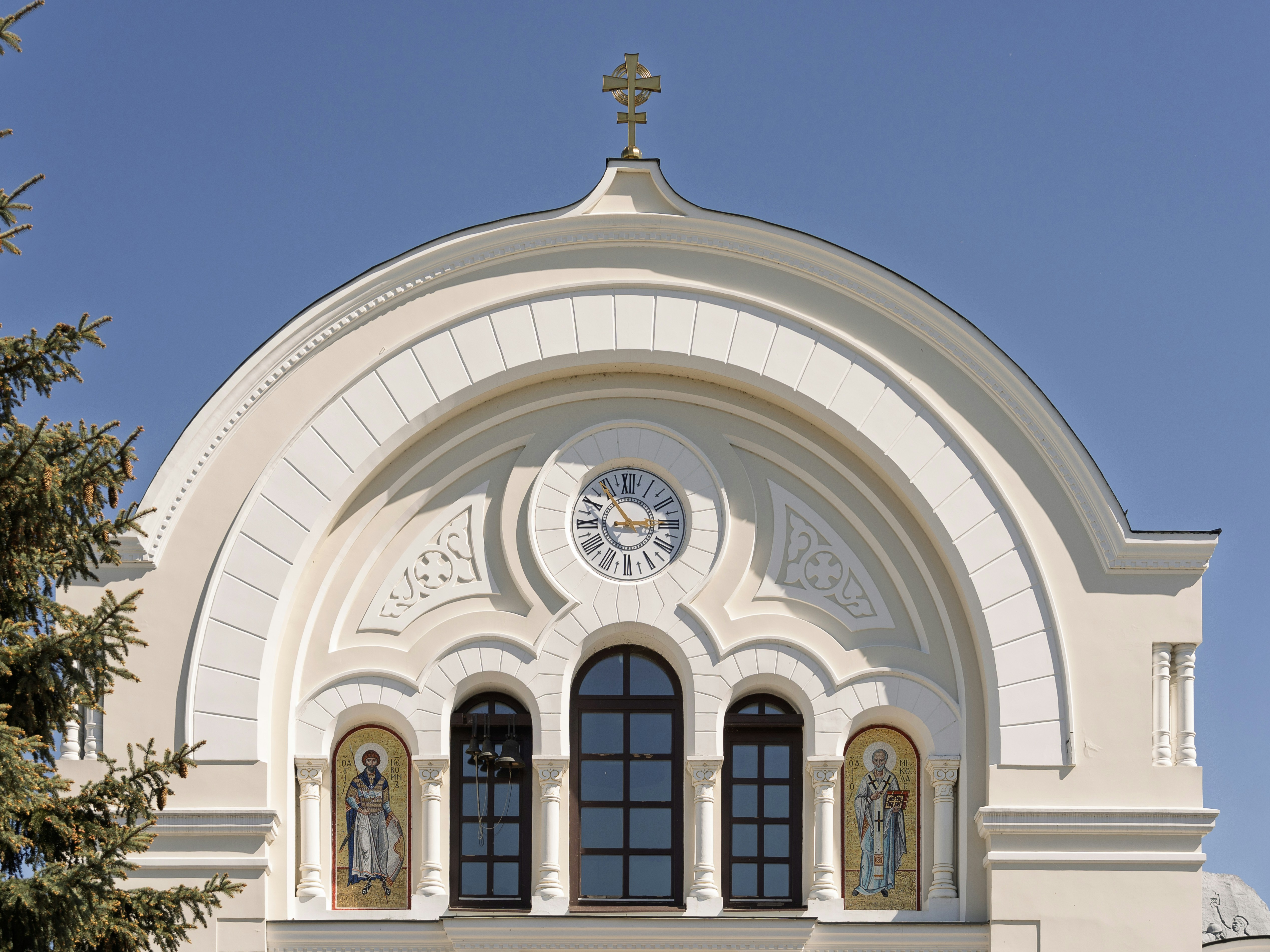 Arched façade of a white Orthodox church with icons