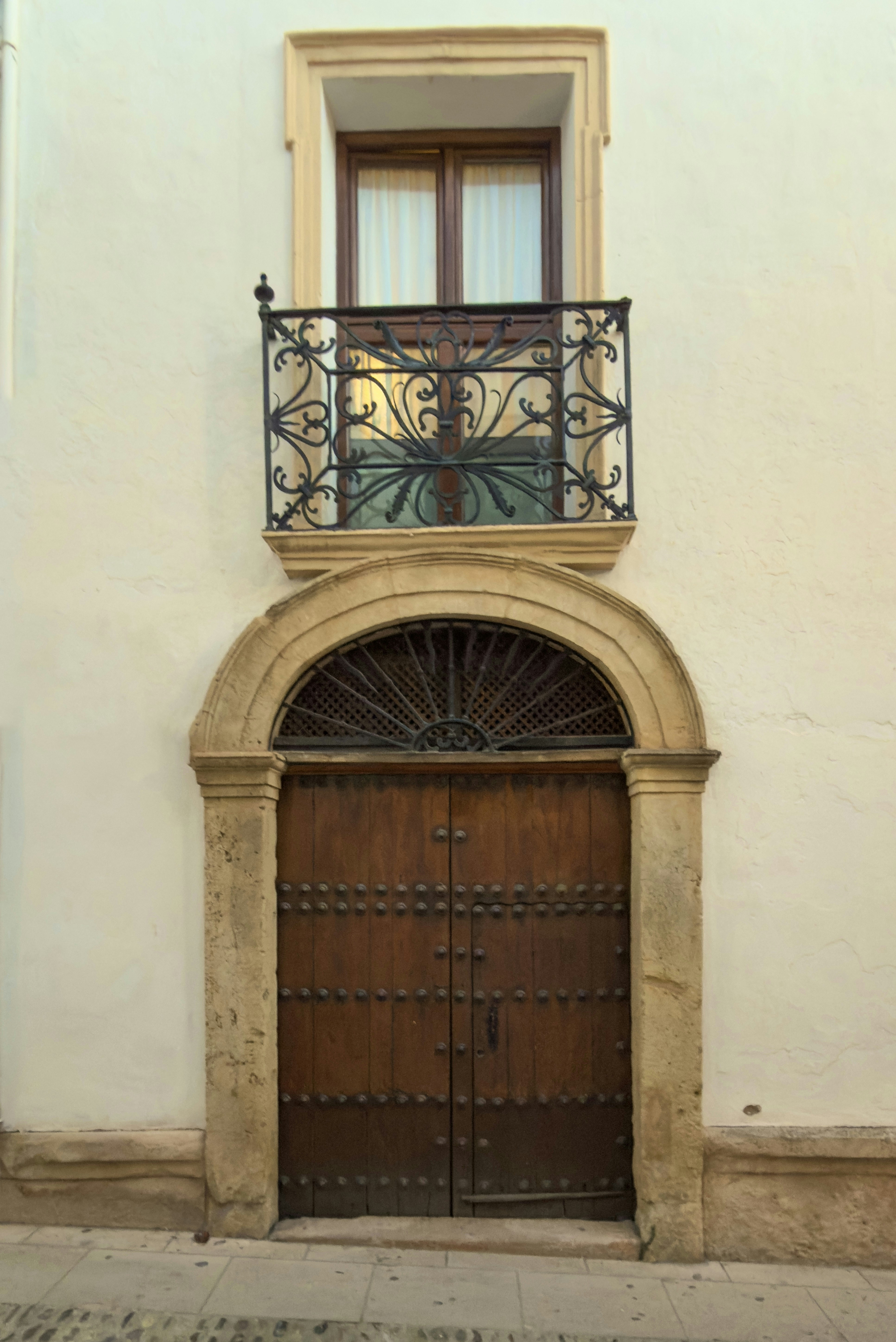 Stone Archway and Iron Balcony: A Timeless Wooden Door