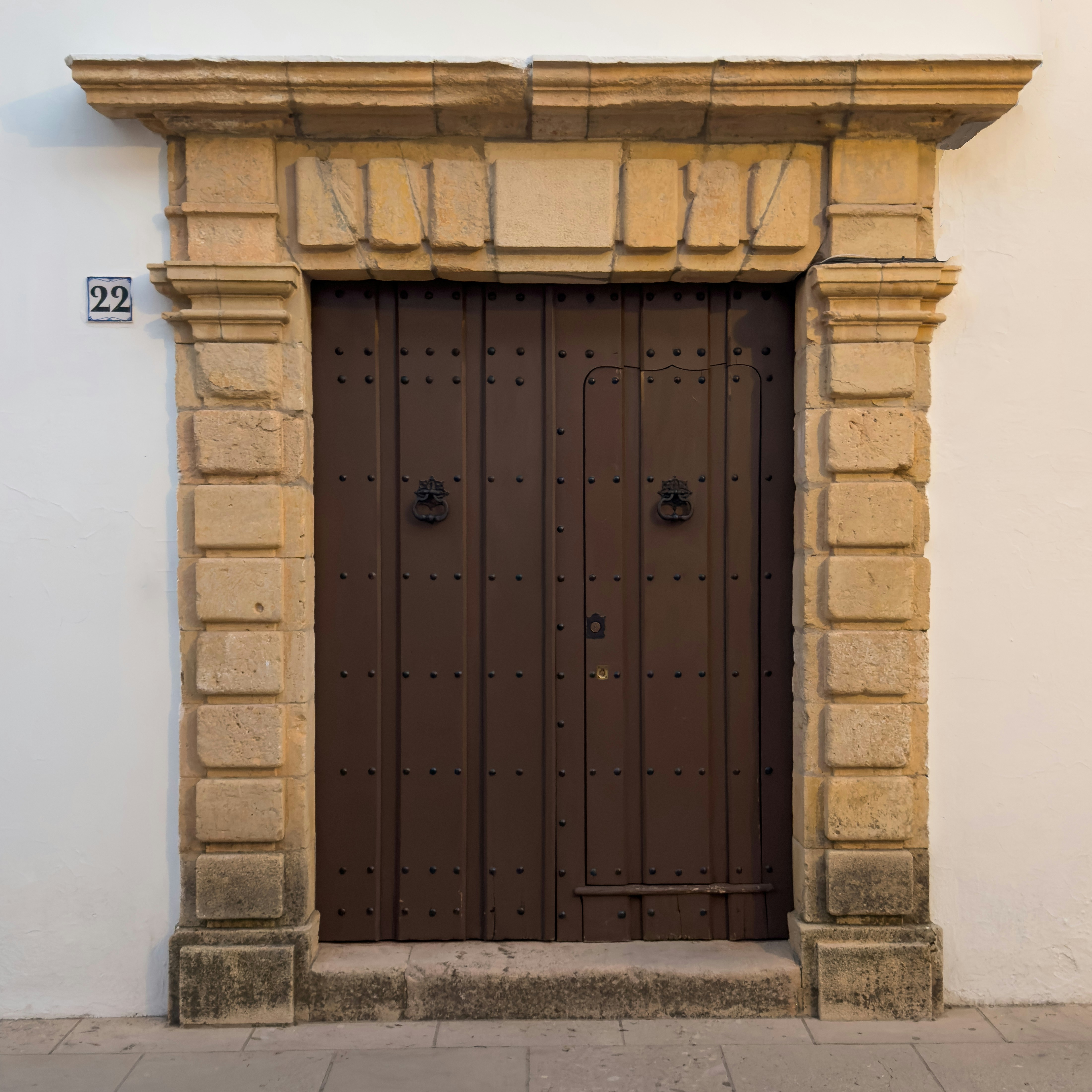 Stone Portal with Iron Door: A Framed Doorway in Soft-Toned Masonry