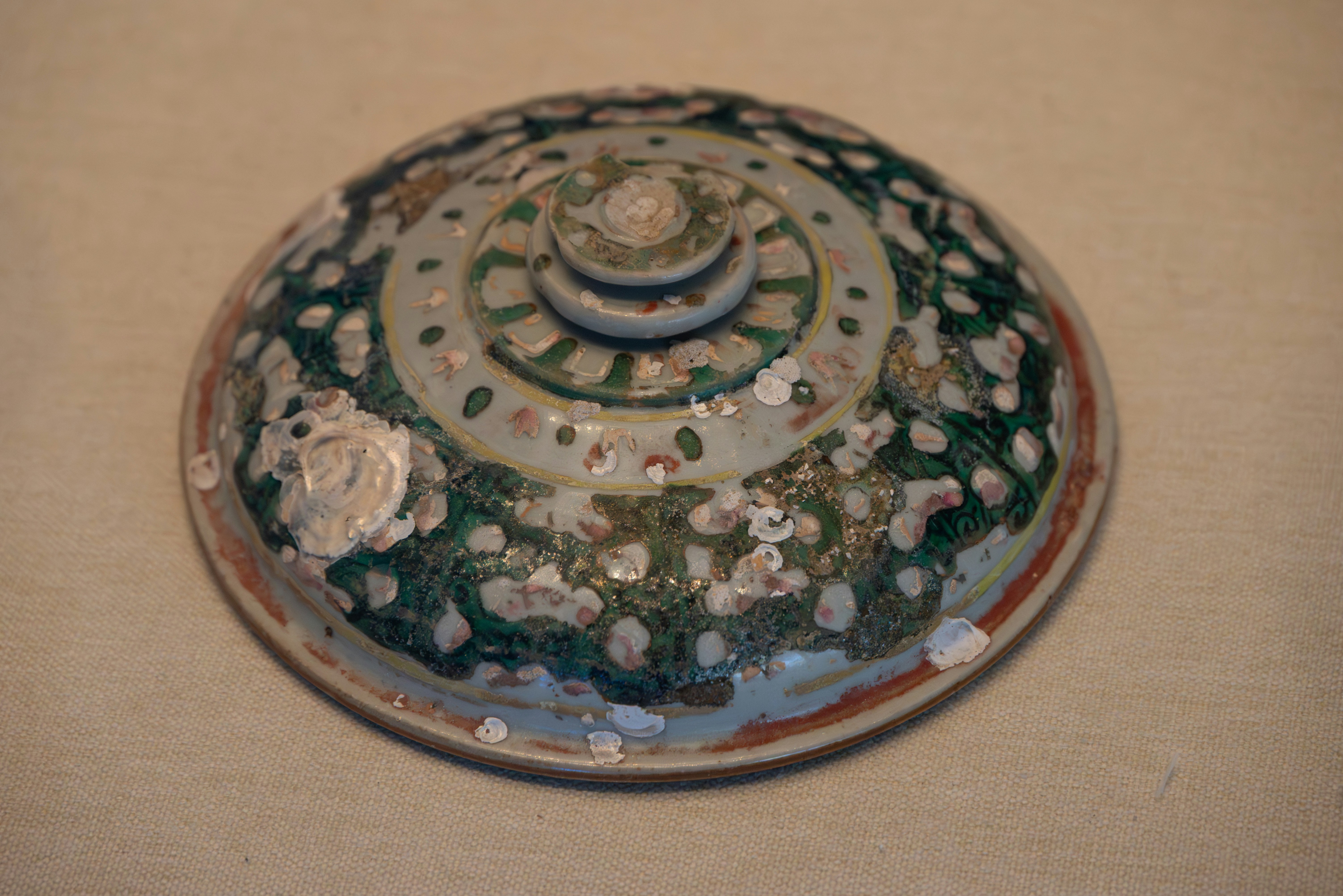 Ceramic kilnsheen: a painted bas-relief domed lid resting on a speckled glaze