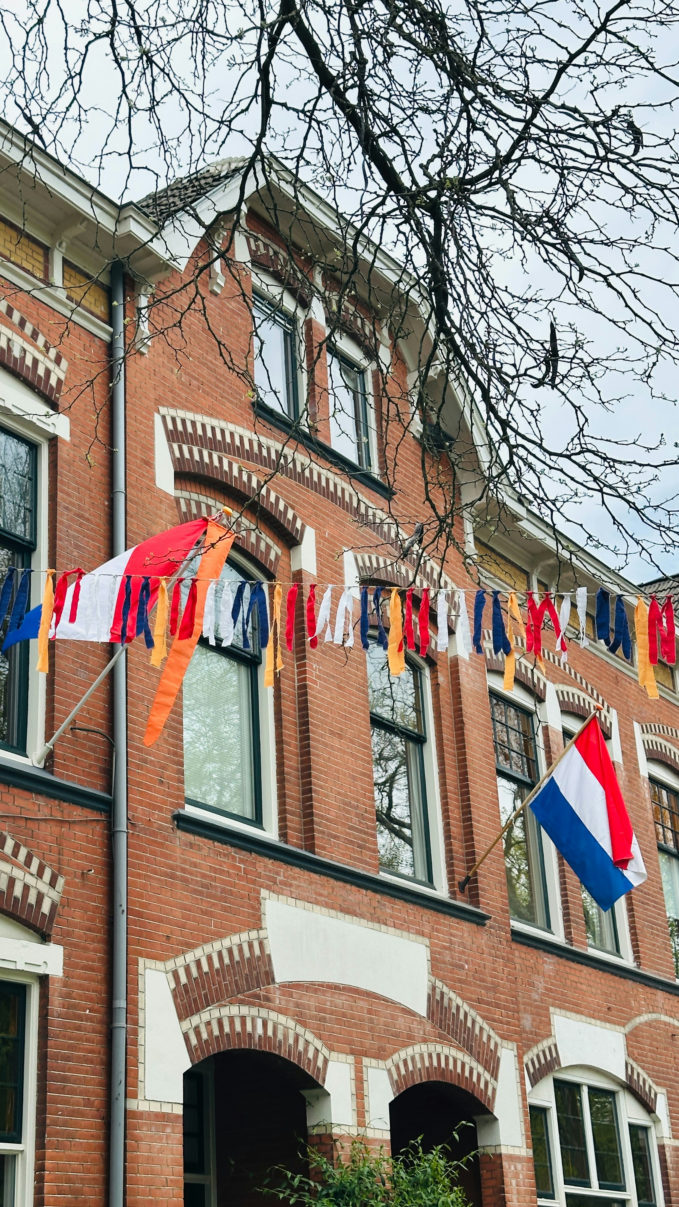 Brick Facade and Festive Banner: A Dutch-Flagged Streetscape