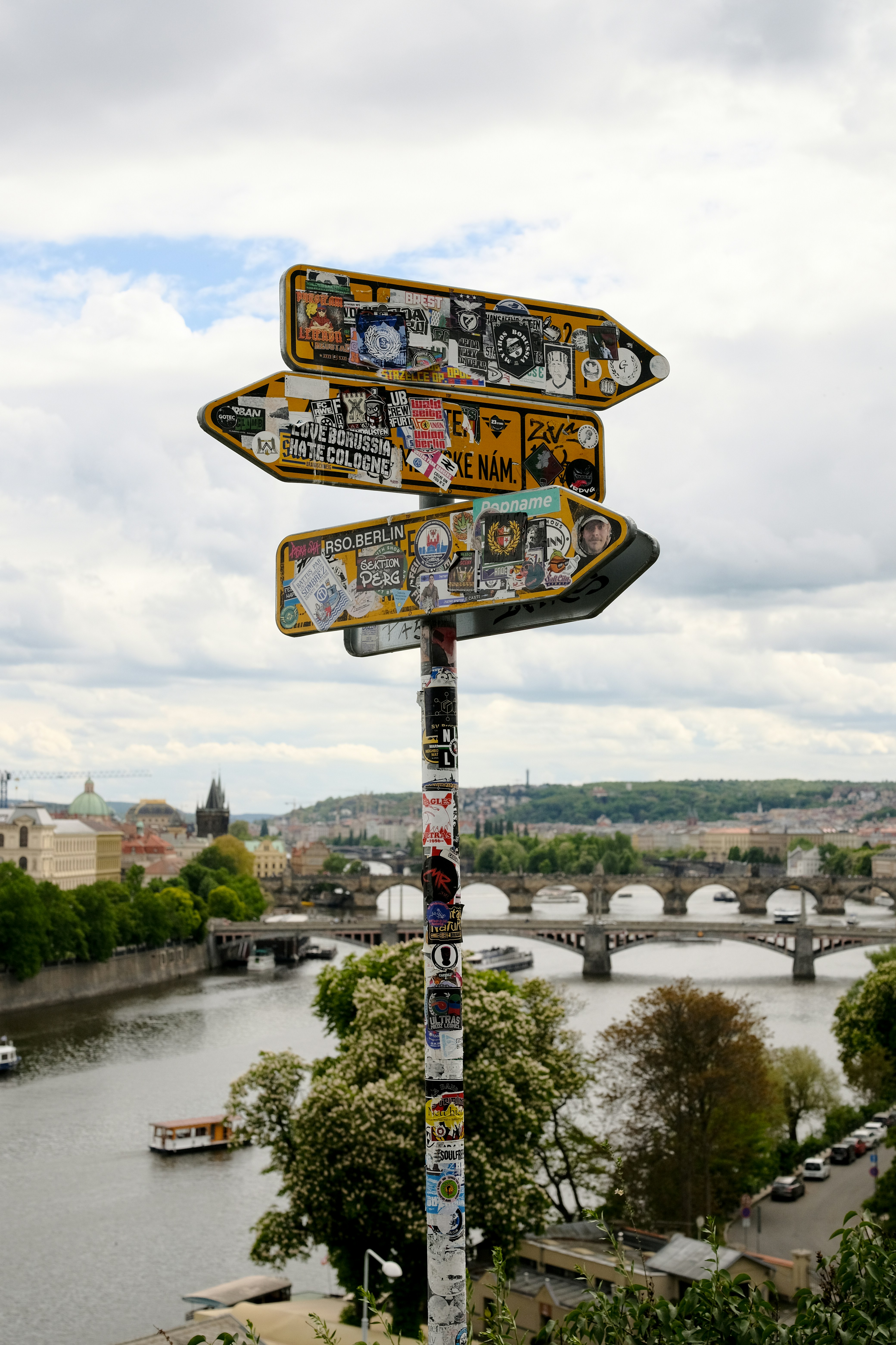 Stickered Signpost Overlooking a City River
