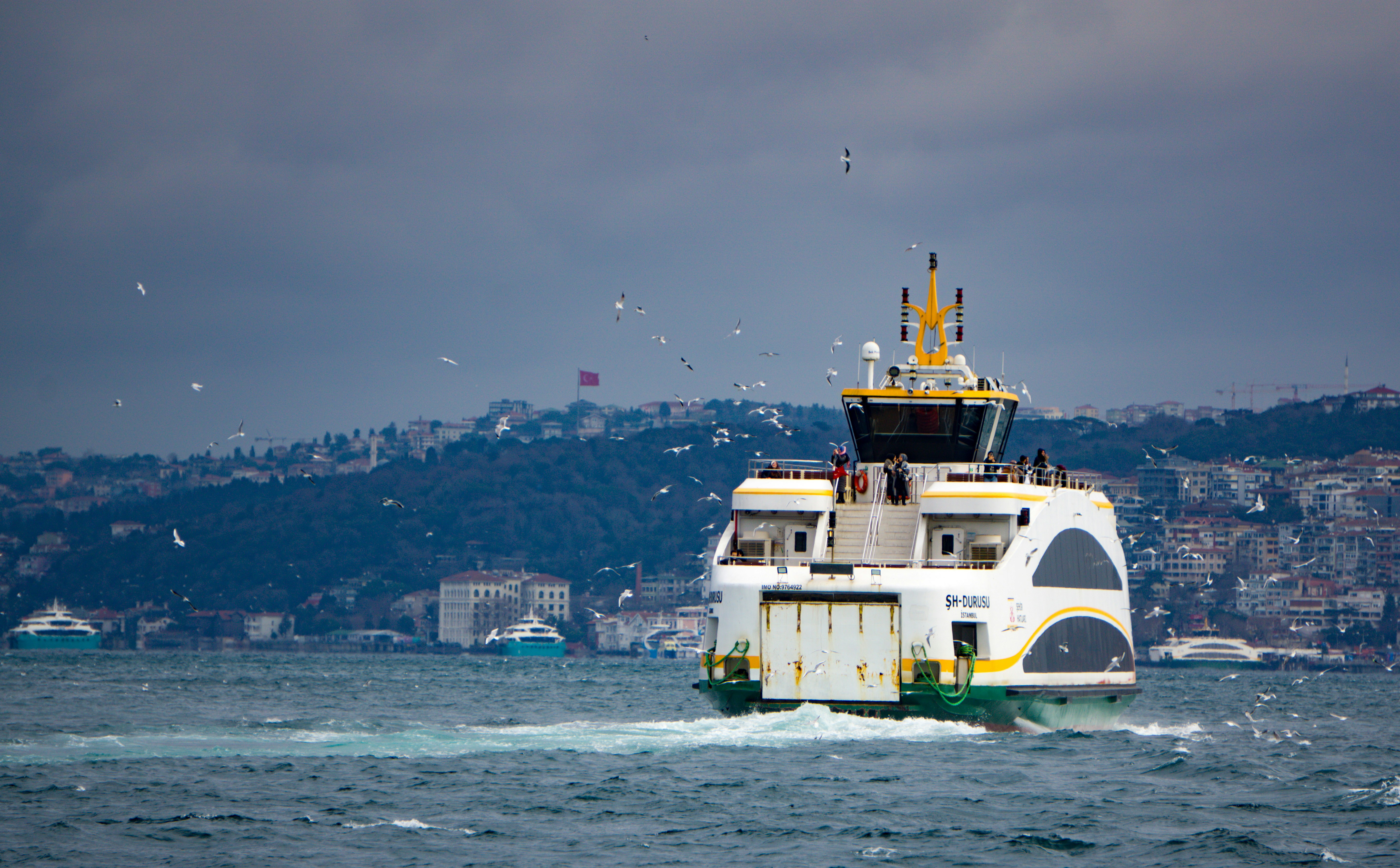 A lone ferry cuts through a seascape toward a distant hillside