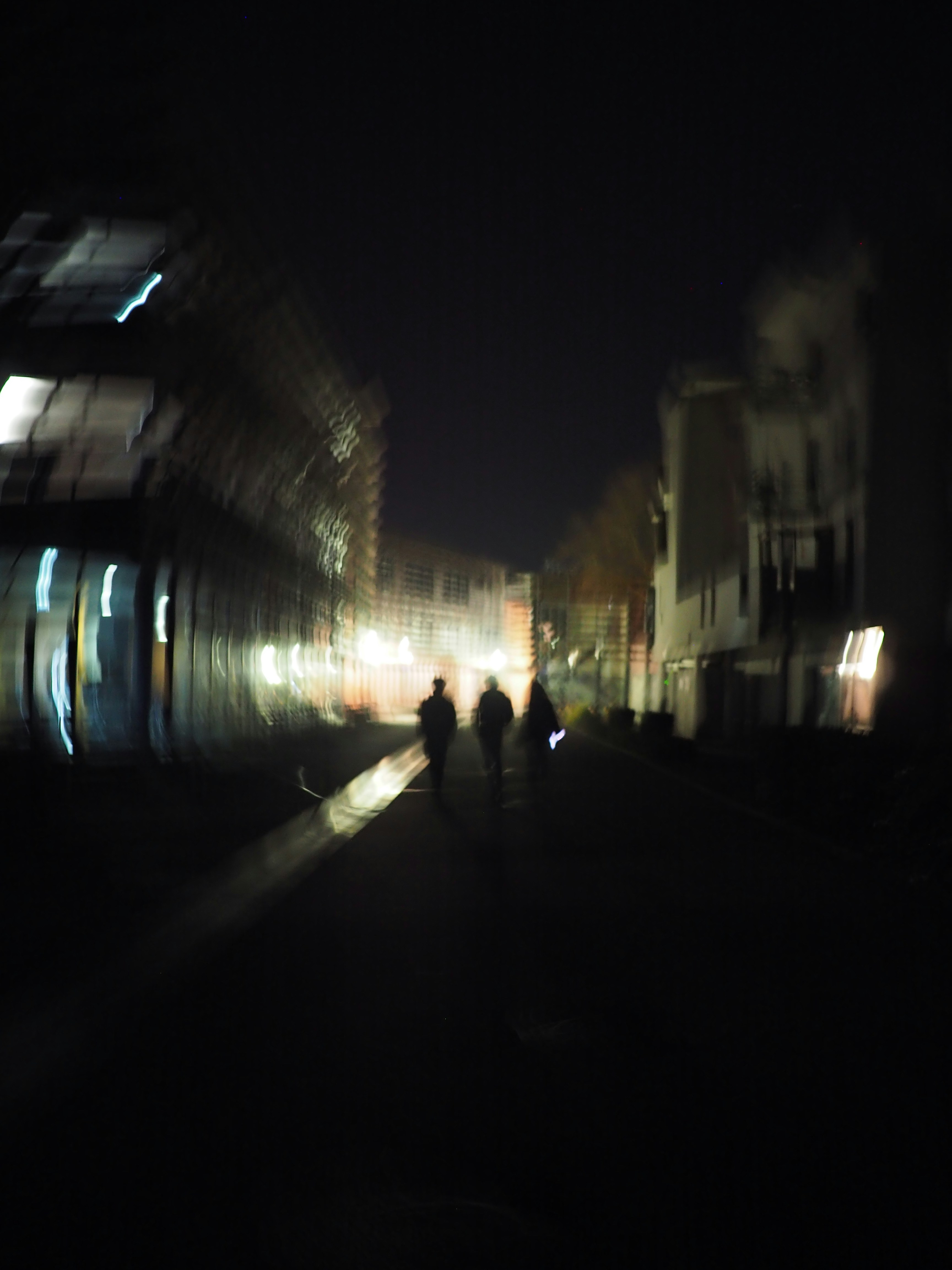 Night Street Blur: Three Silhouettes Amid Neon Glare