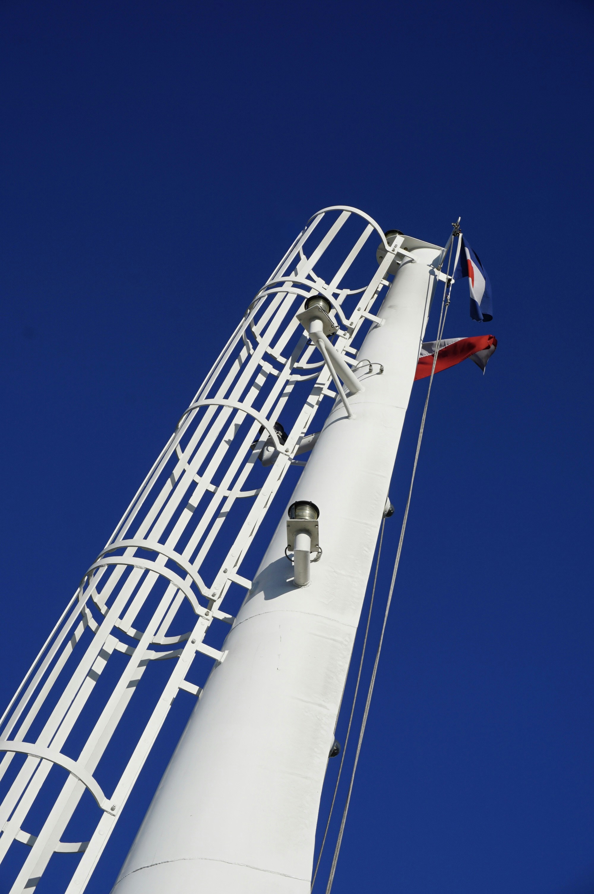 White Lattice Mast Reaching Toward a Deep Blue Sky