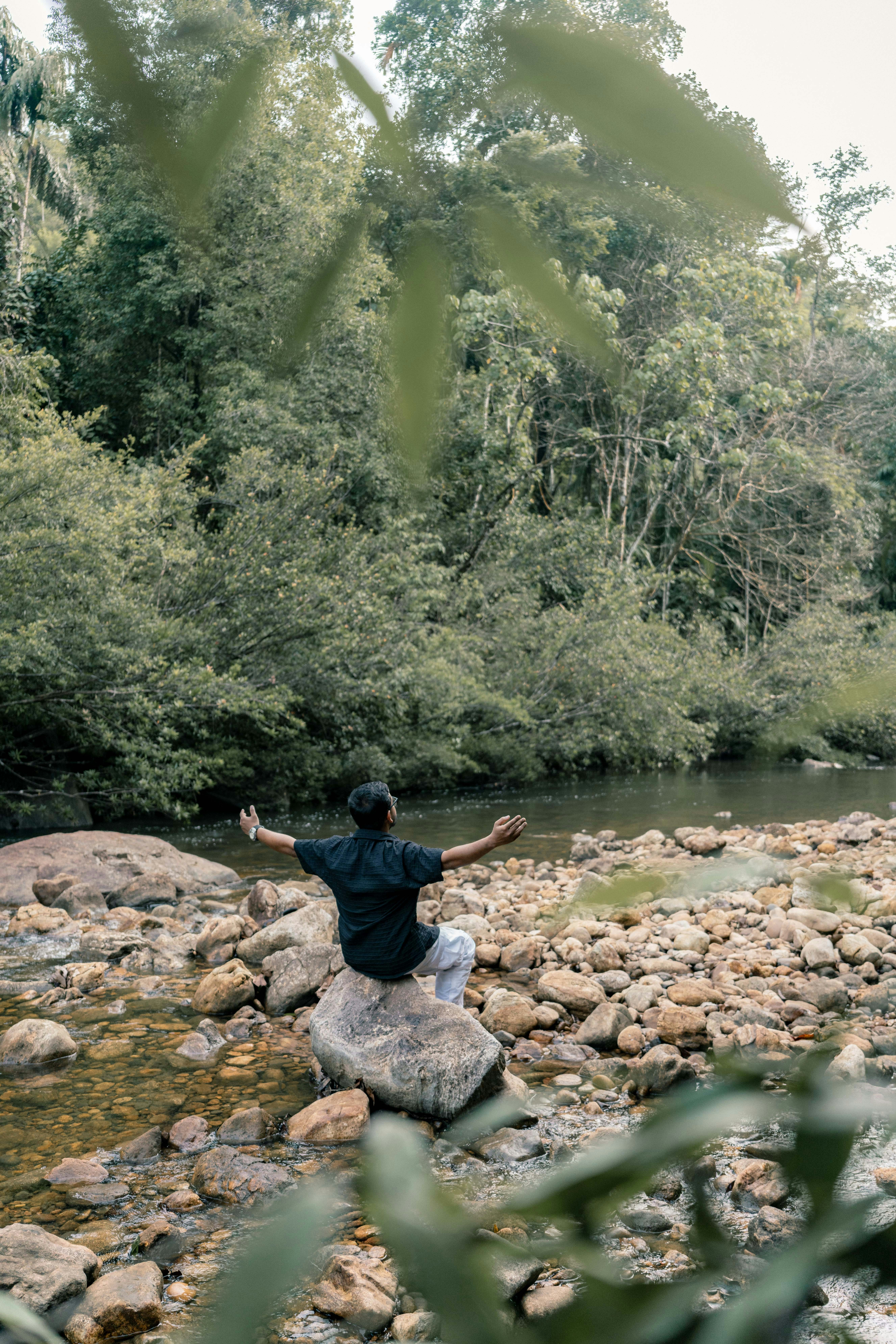 Traveler on a granite throne: a lone figure amid a forest river