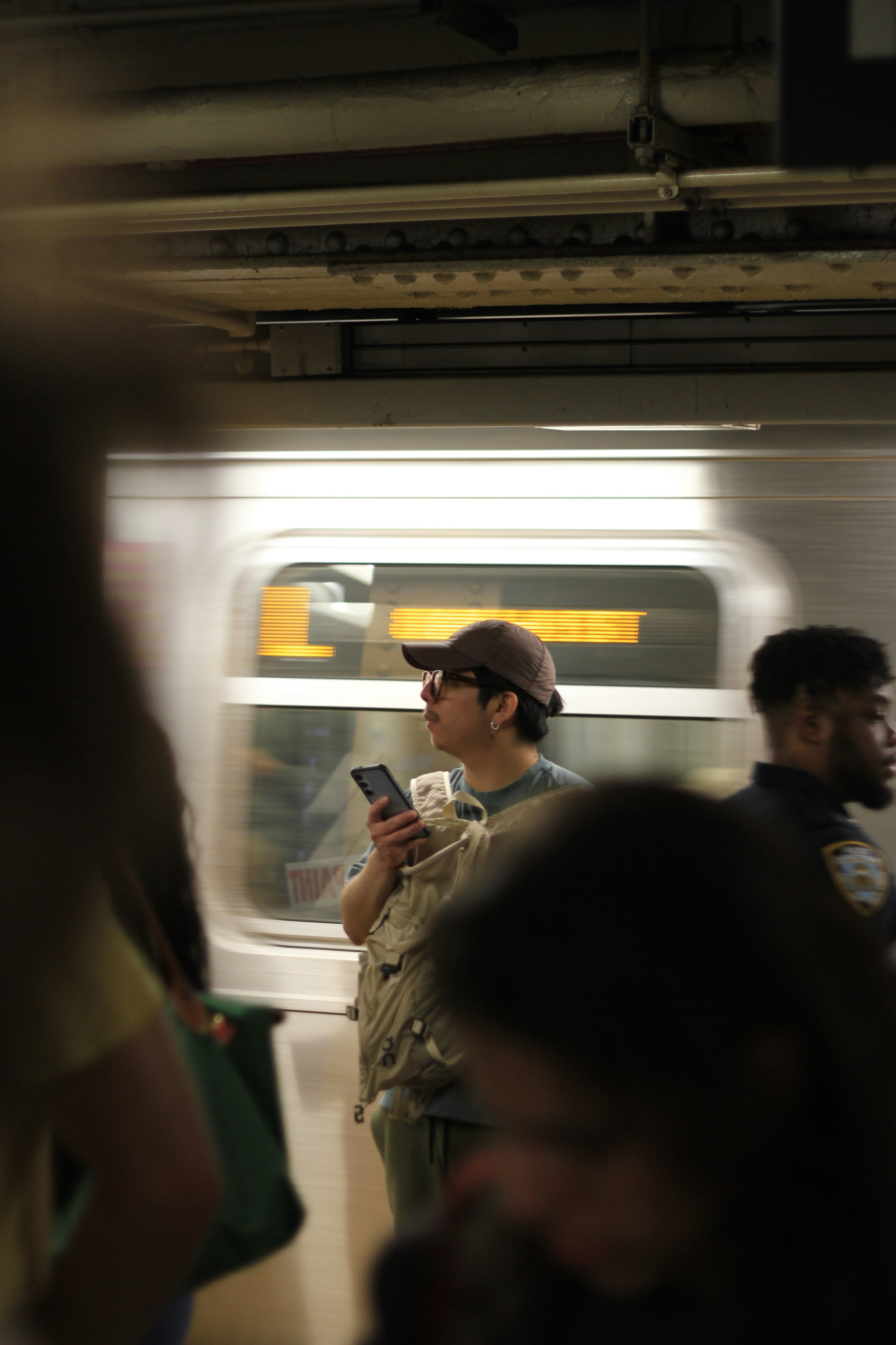 Subway Moment: Man in Cap Glances at His Phone as Train Blurs by