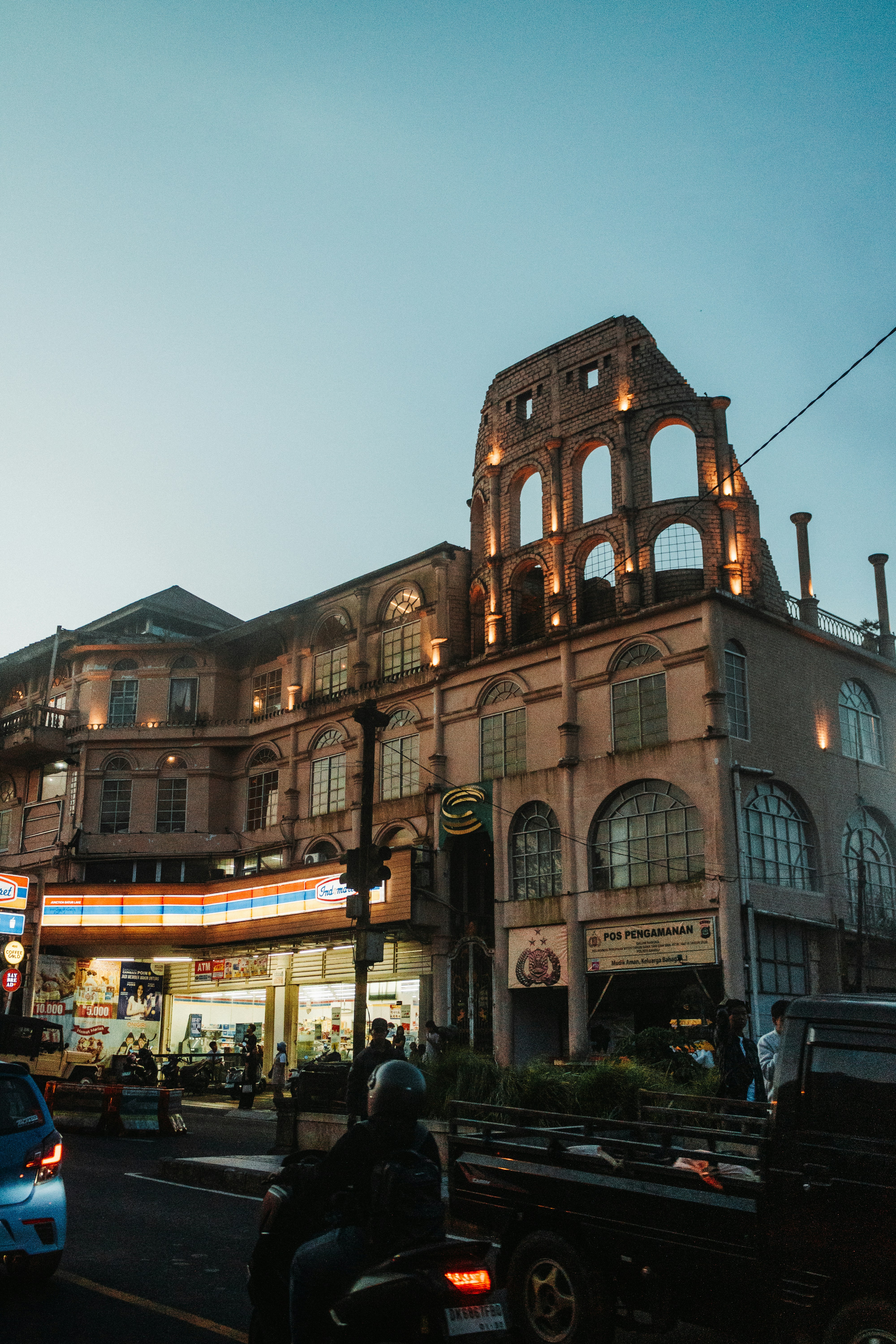 Historic brick ruin towering over a lively street at dusk
