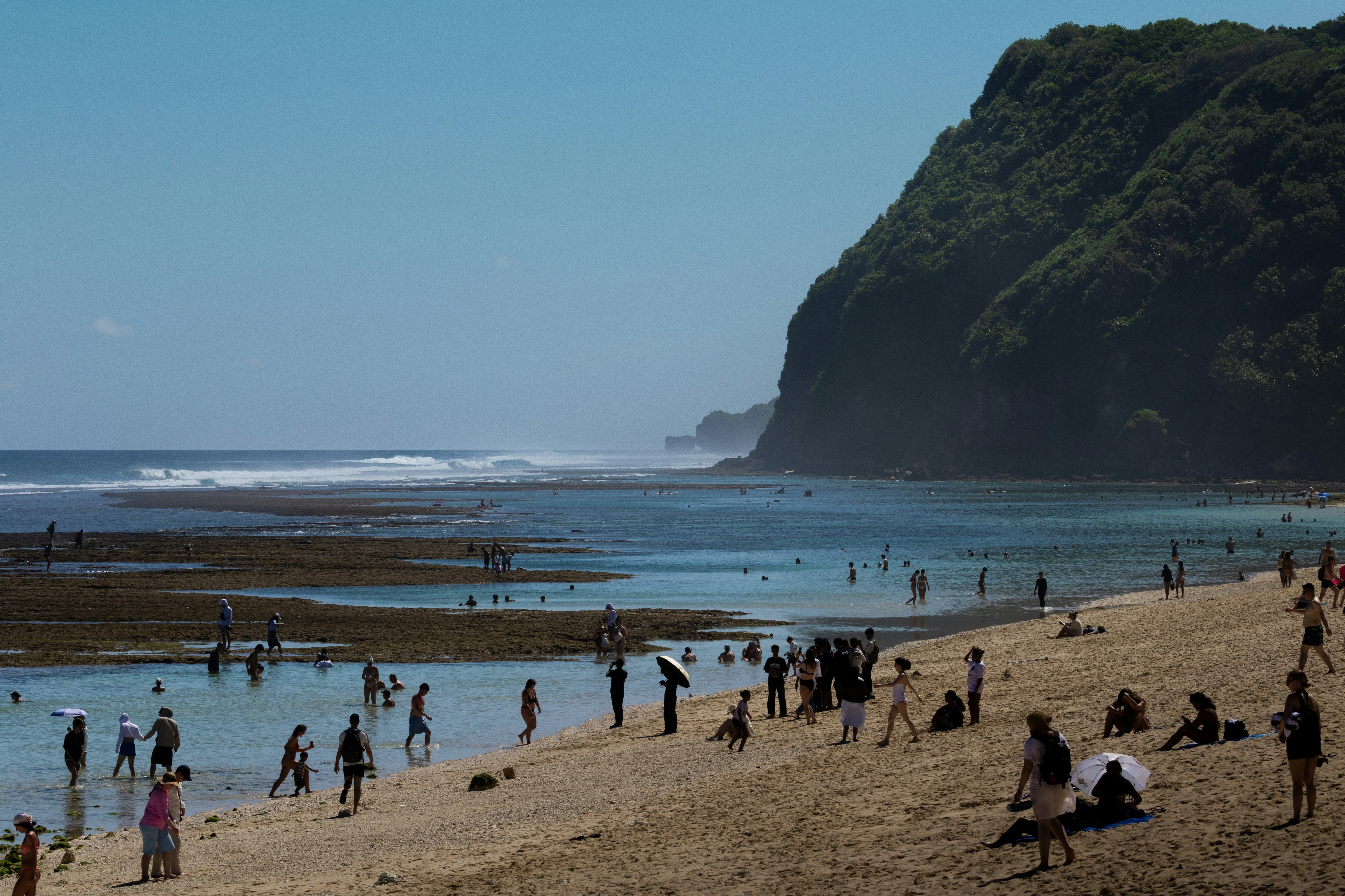 Shoreline Confluence: Sunlit Beach Amid a Cliff-Guarded Horizon