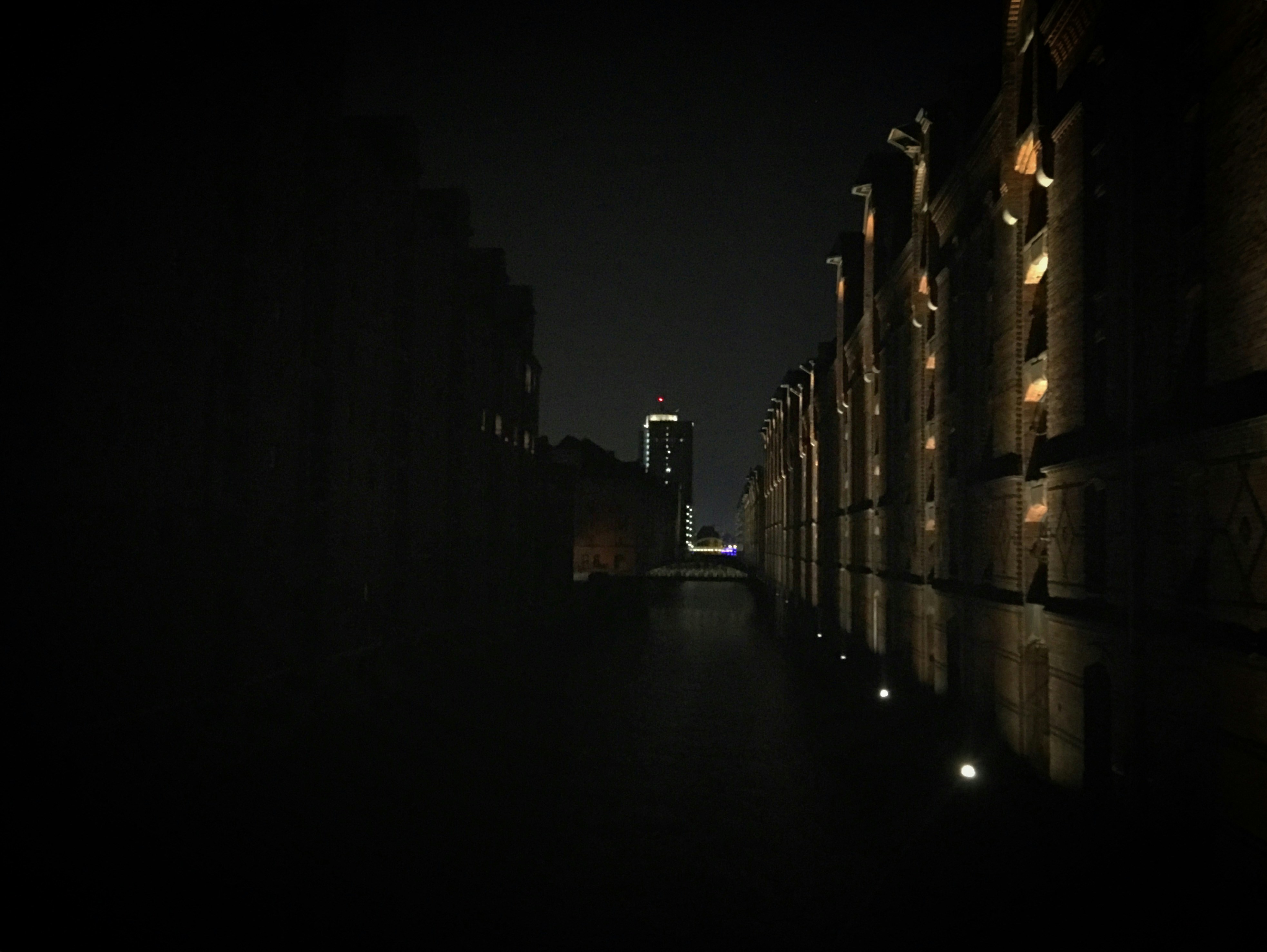 A Narrow Canal Corridor Bordered by Historic Brick Walls at Night